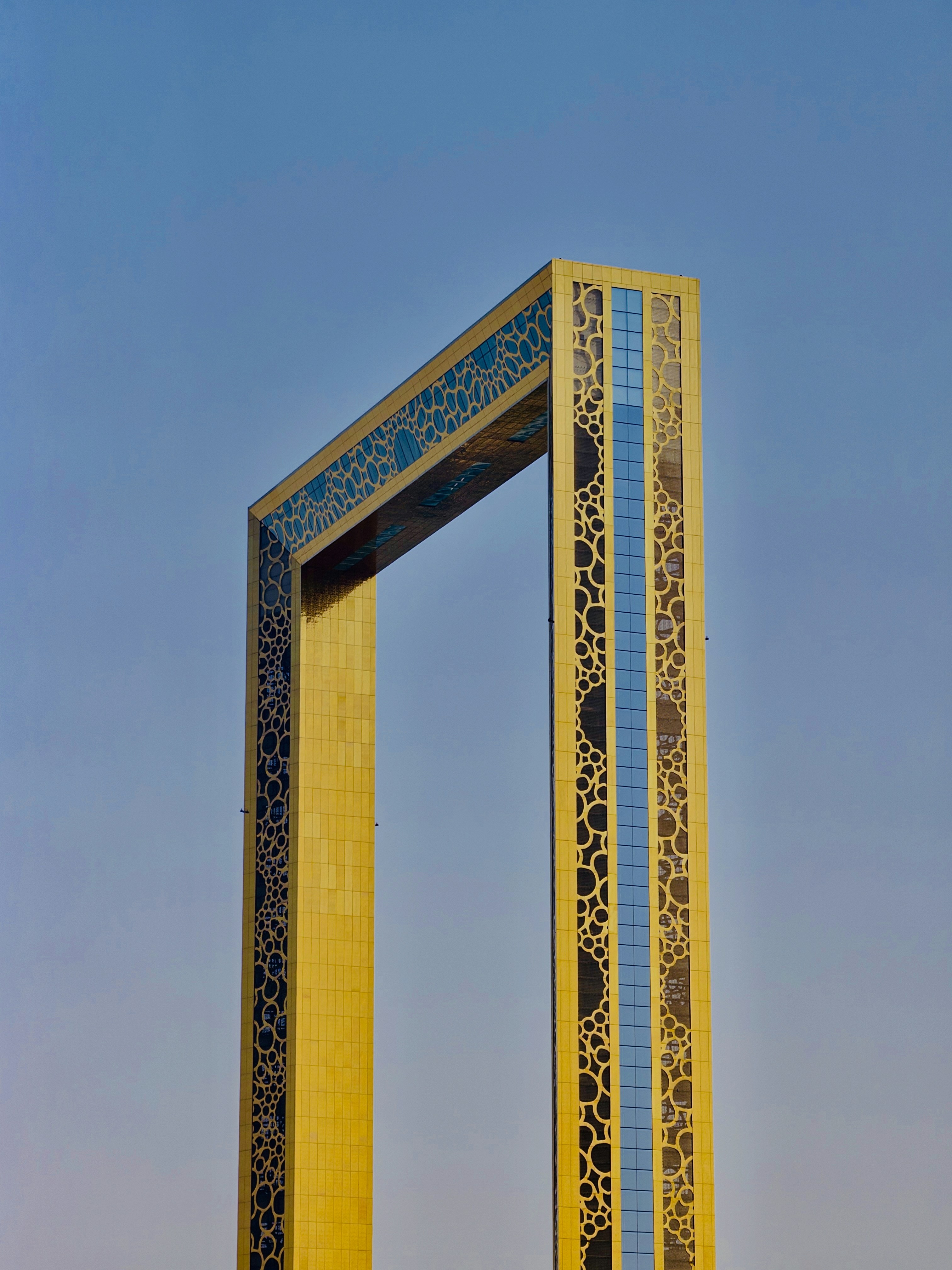 Dubai frame | A tall golden frame structure against a clear blue sky.
