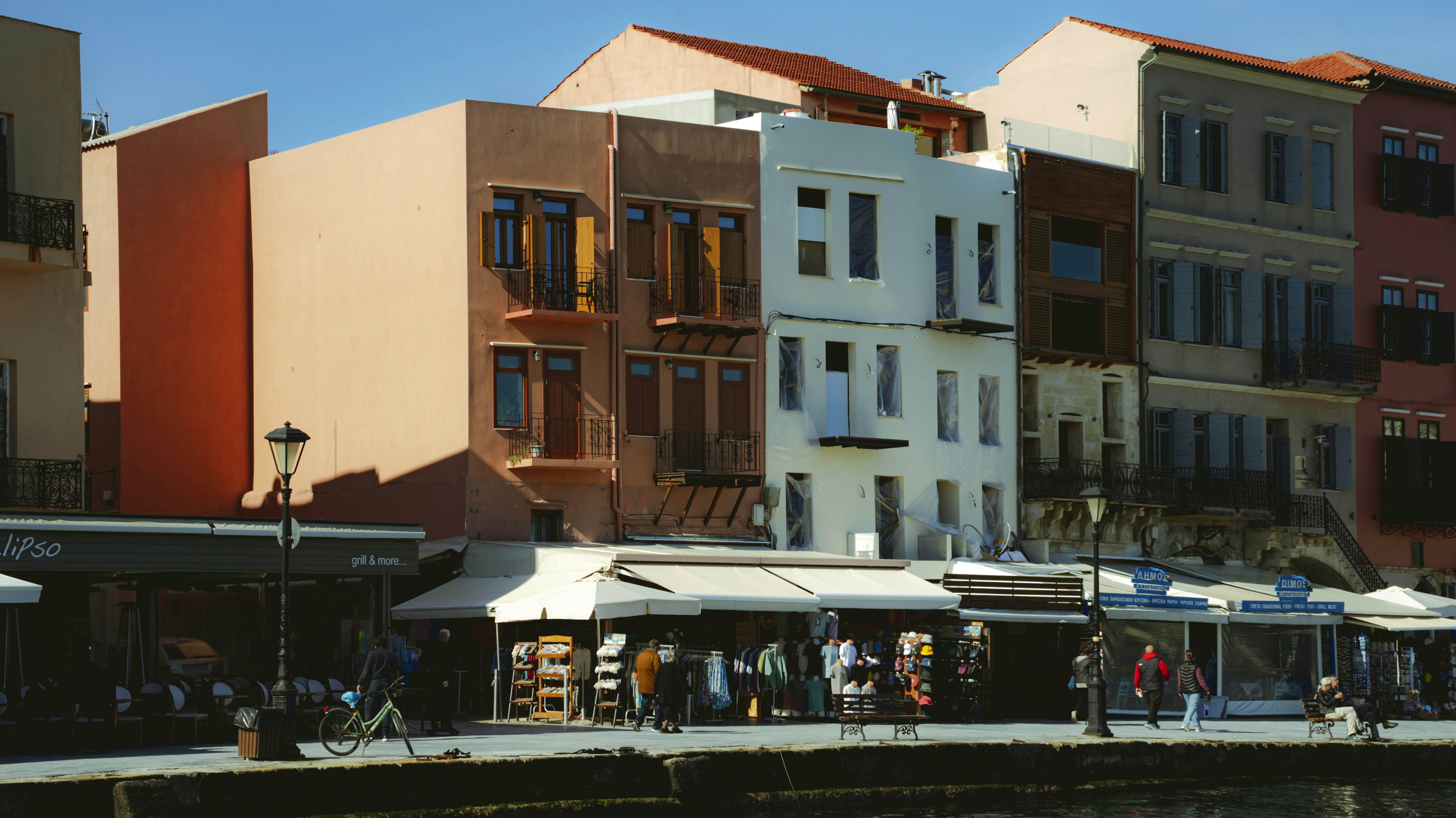 Colorful buildings line a waterfront promenade with shops.