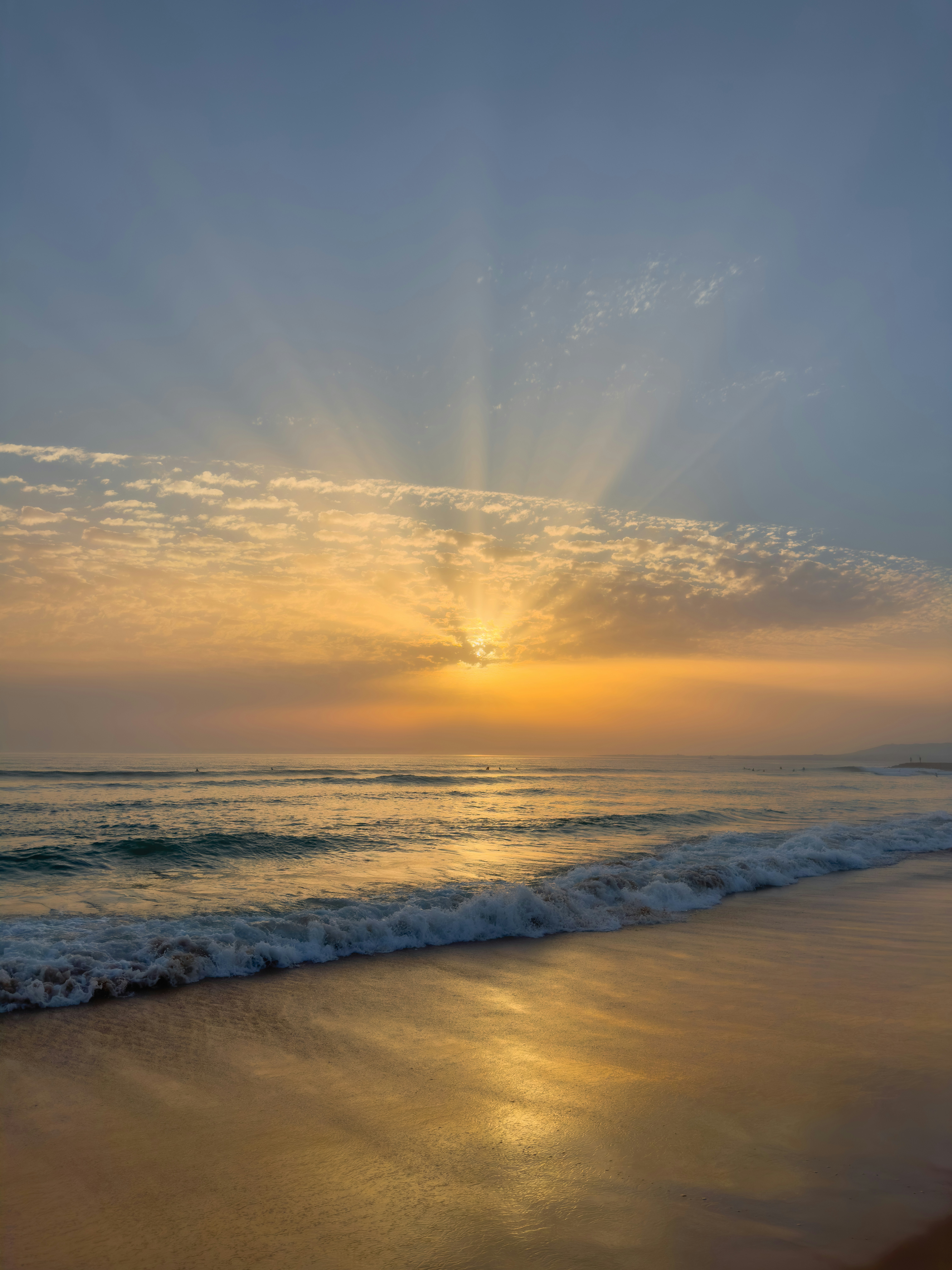 Sun rays beaming through clouds over ocean waves