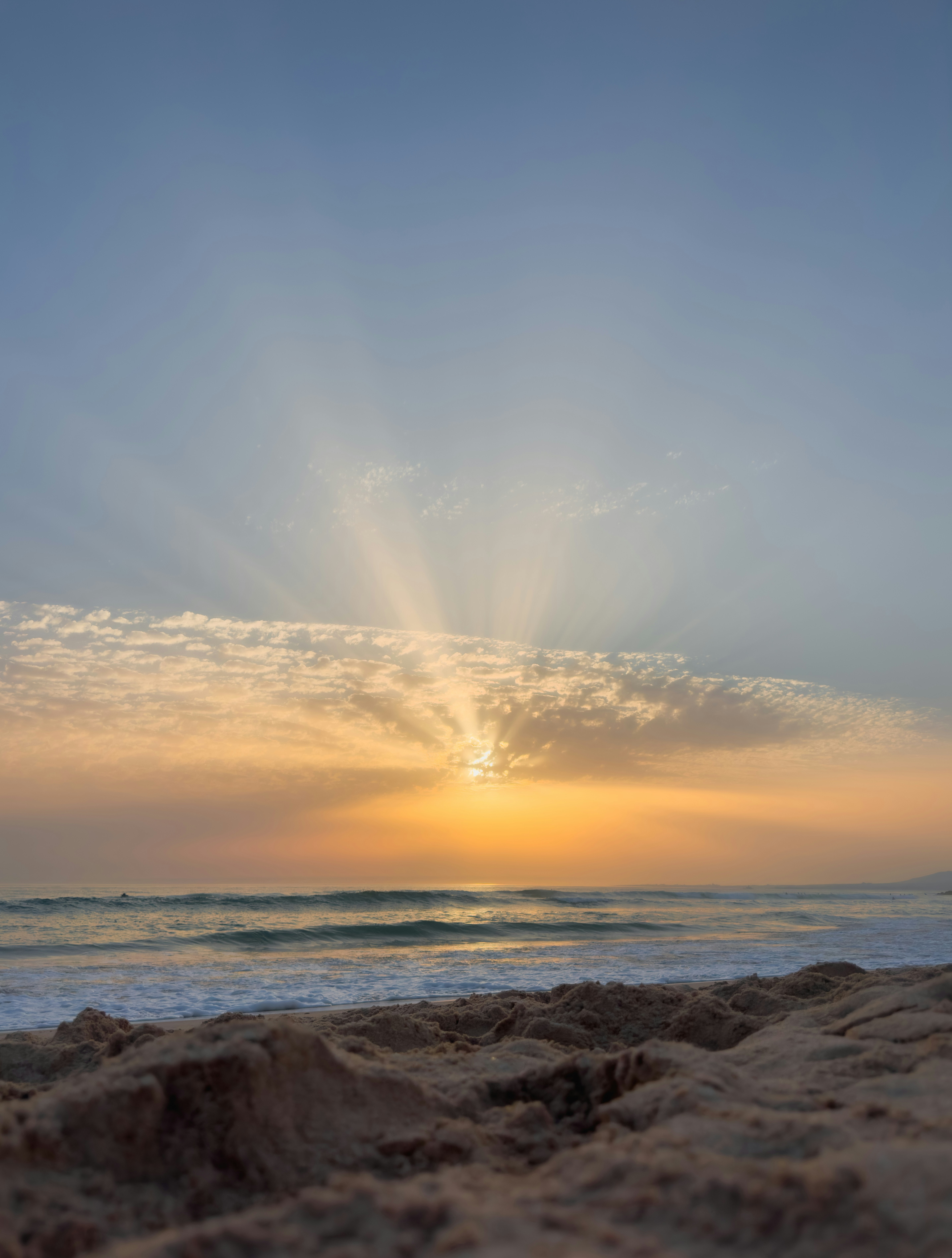 Sunrise over the ocean with sandy beach foreground.