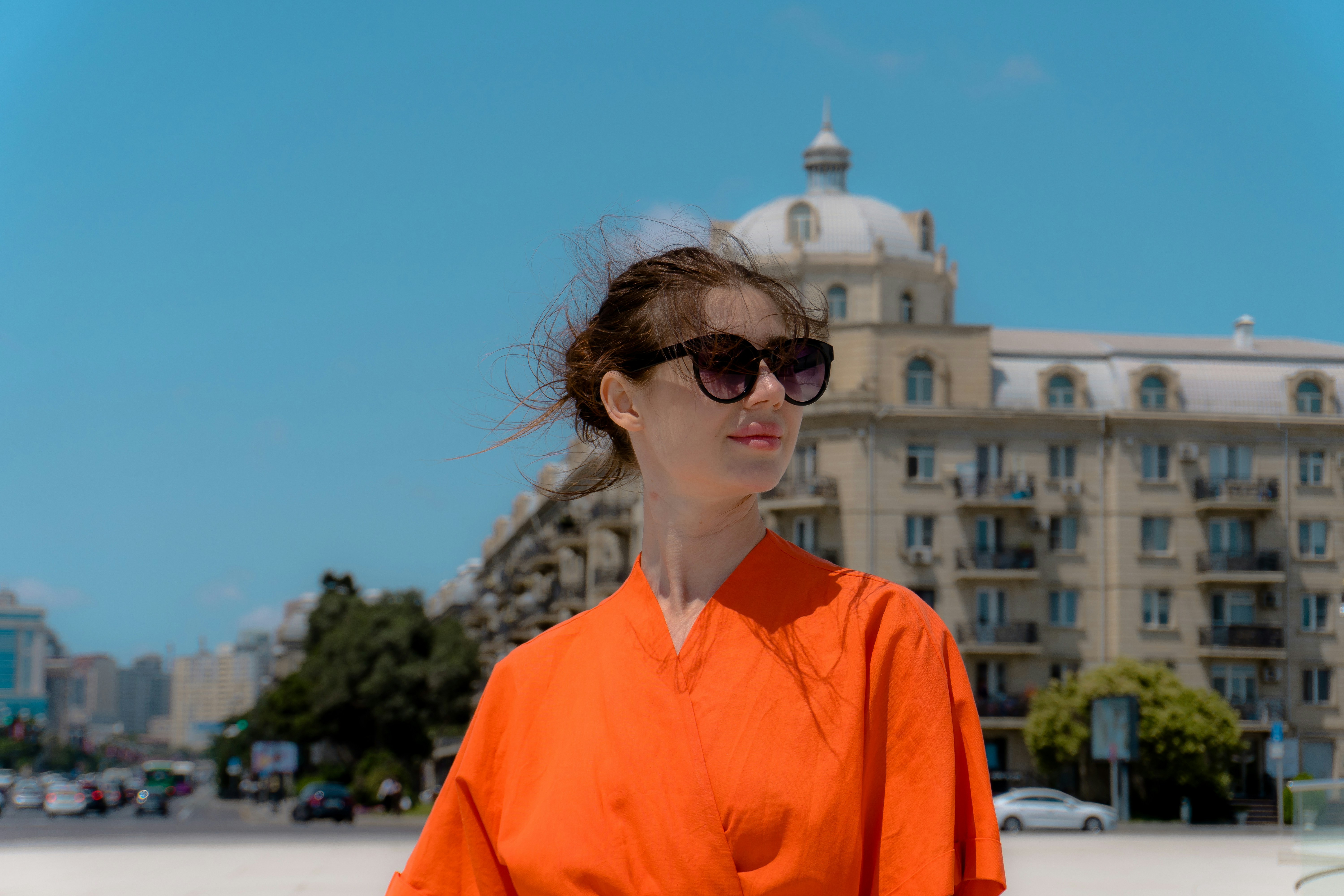 Orange Attire in Urban Light: A Portrait Before a Grand Facade