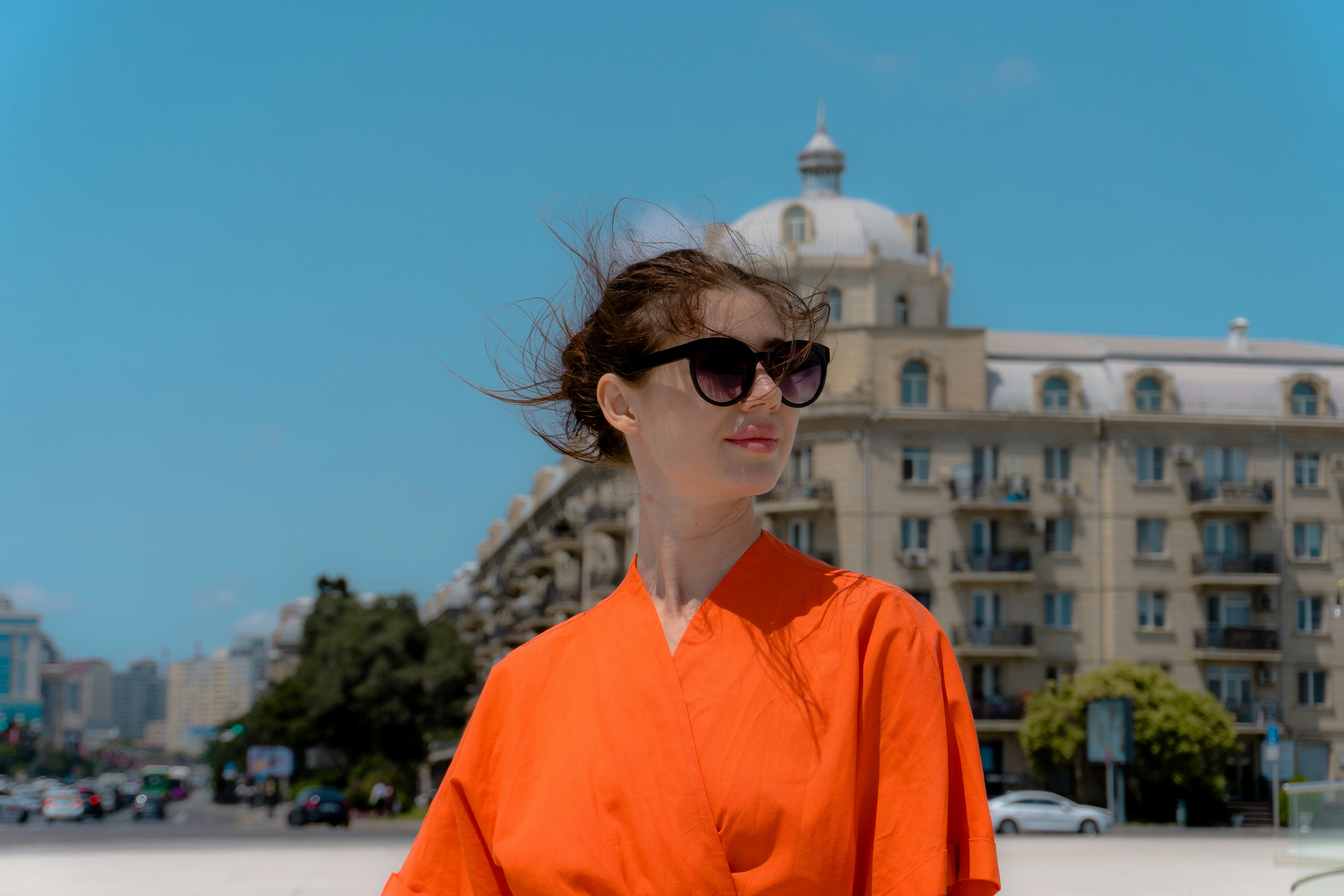 Woman in orange outfit with sunglasses in city