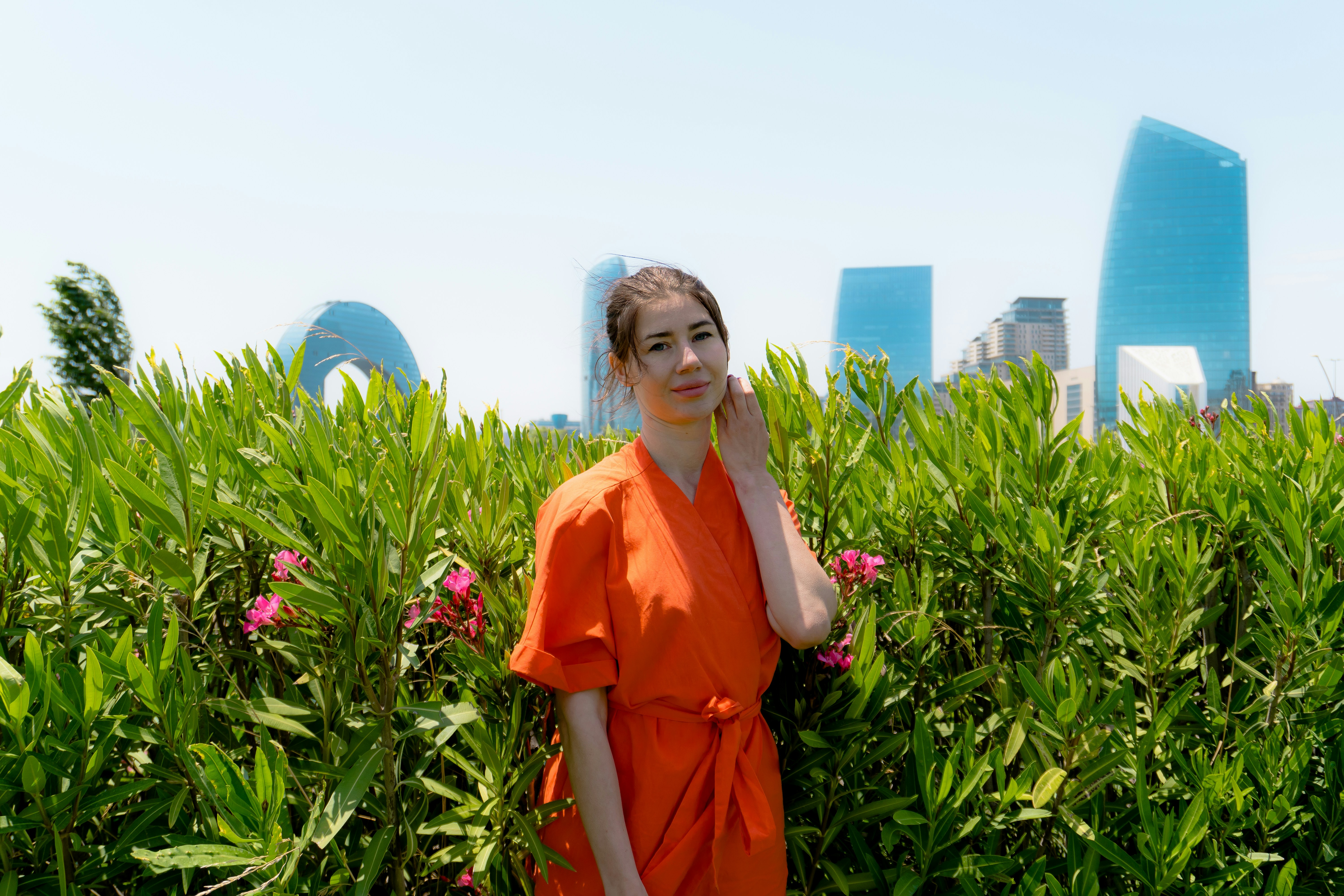 Orange dress in a green hedge with city skyline
