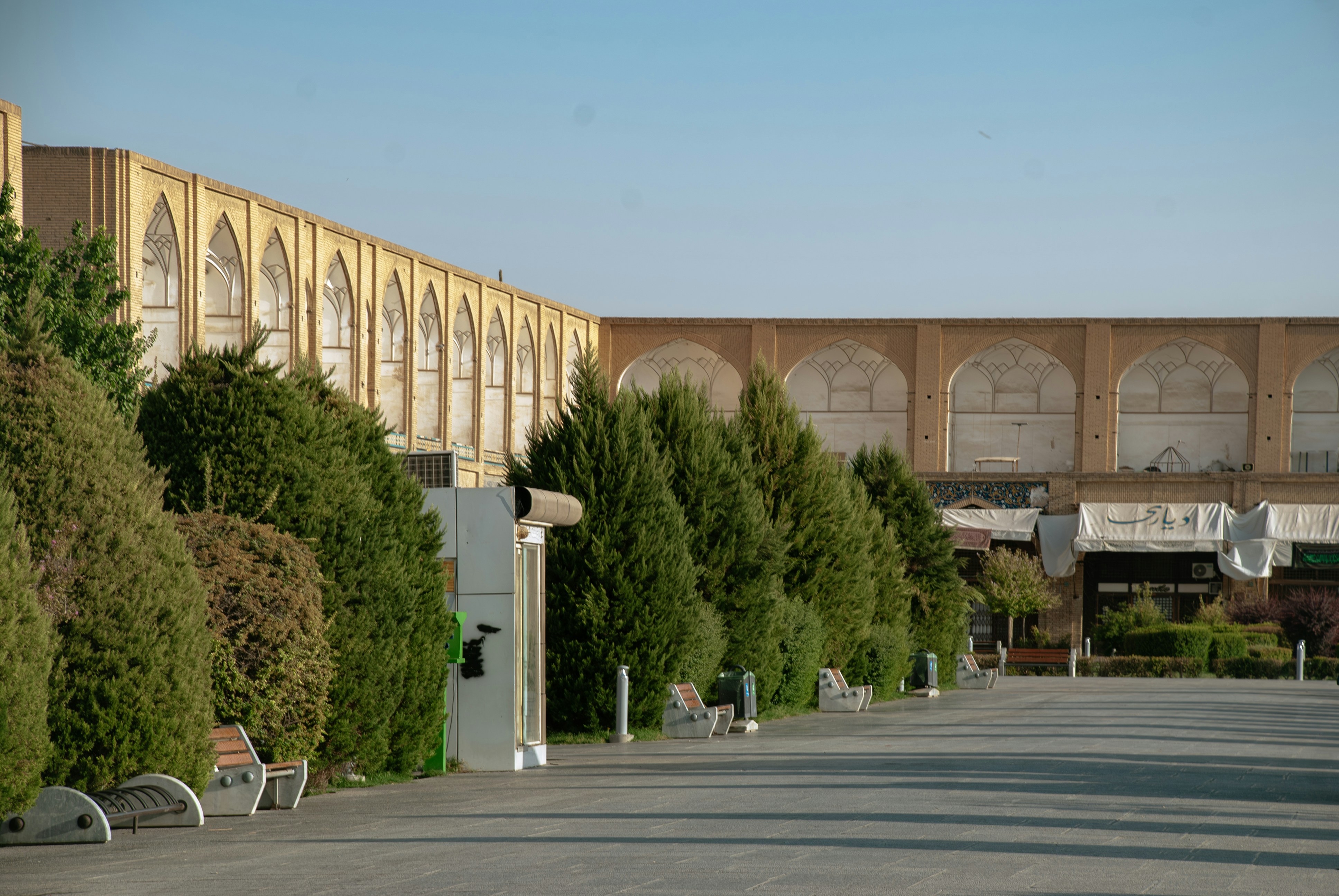 Pathway lined with lush greenery leading to a historic building, showcasing a blend of natural and architectural beauty.