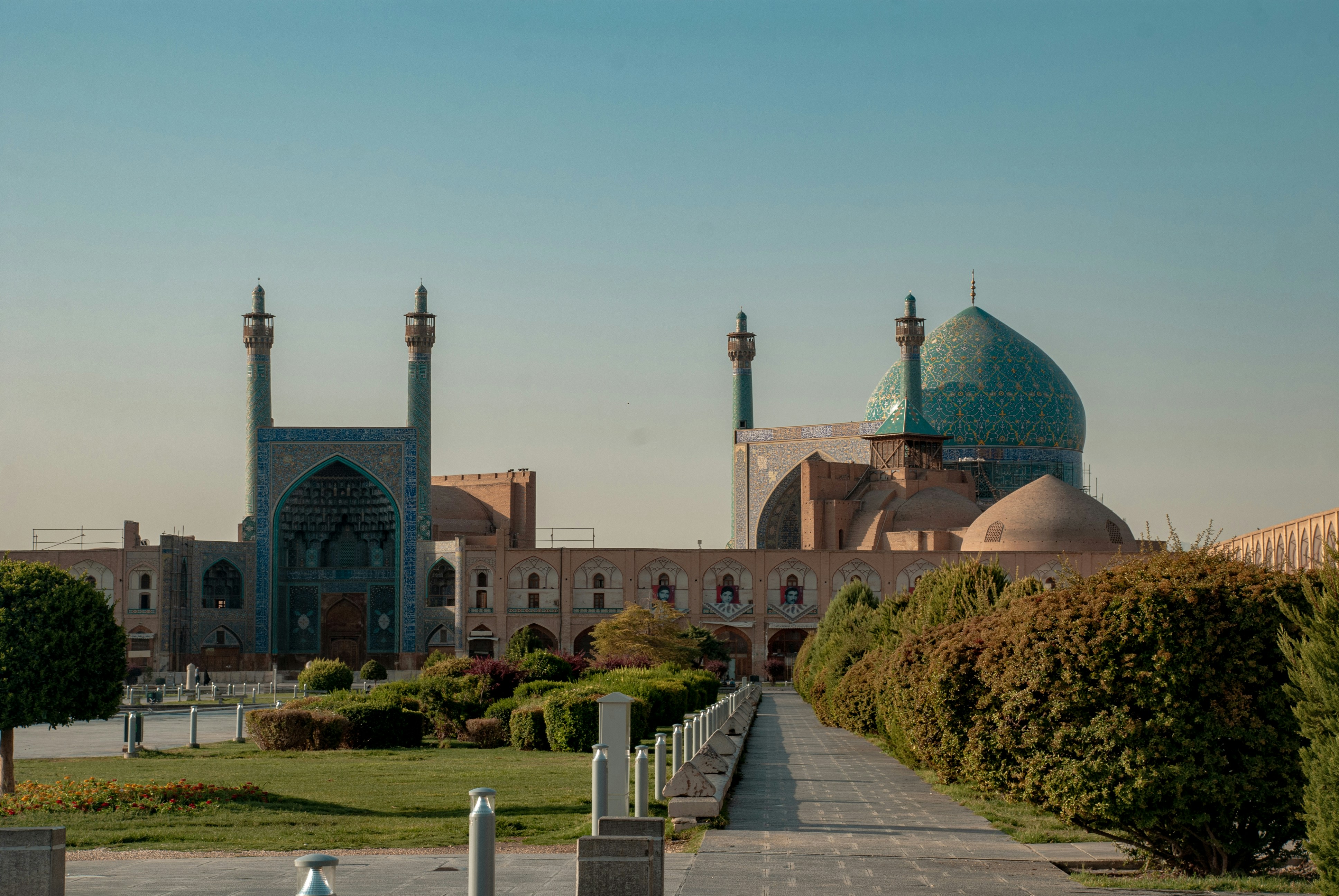 Historic mosque complex featuring intricate tile work and lush greenery in the foreground.