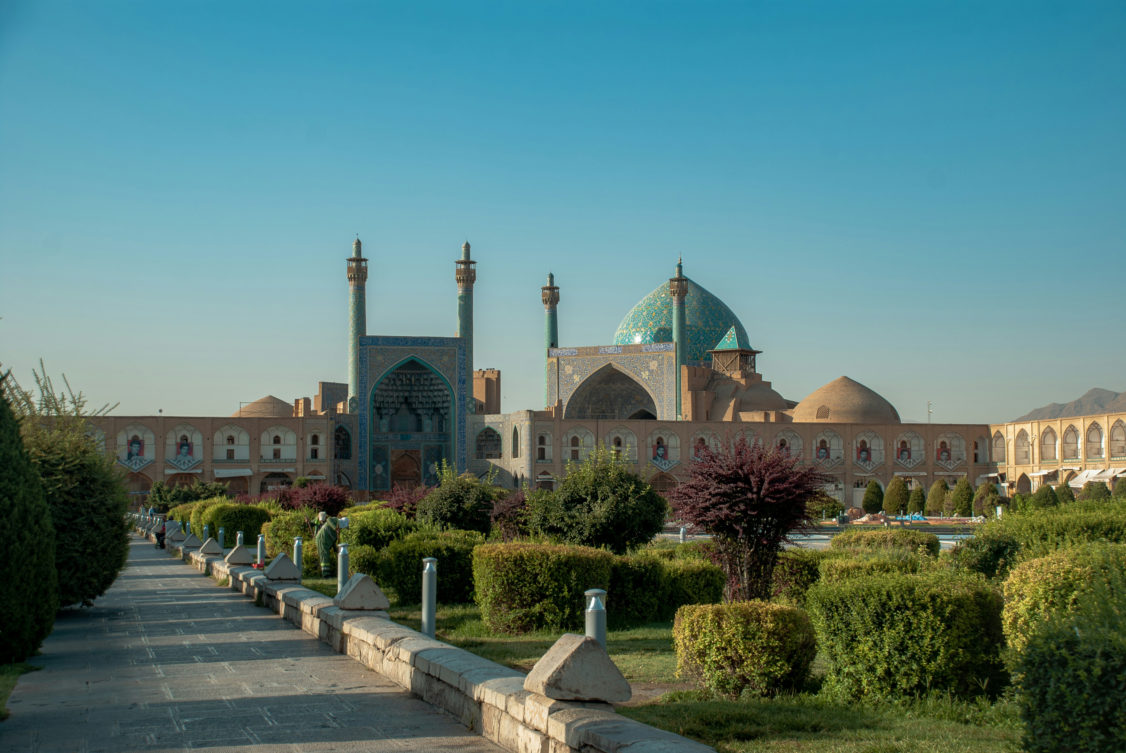 Historic mosque complex framed by lush greenery and a clear blue sky. The intricate designs and domes evoke a sense of cultural richness.