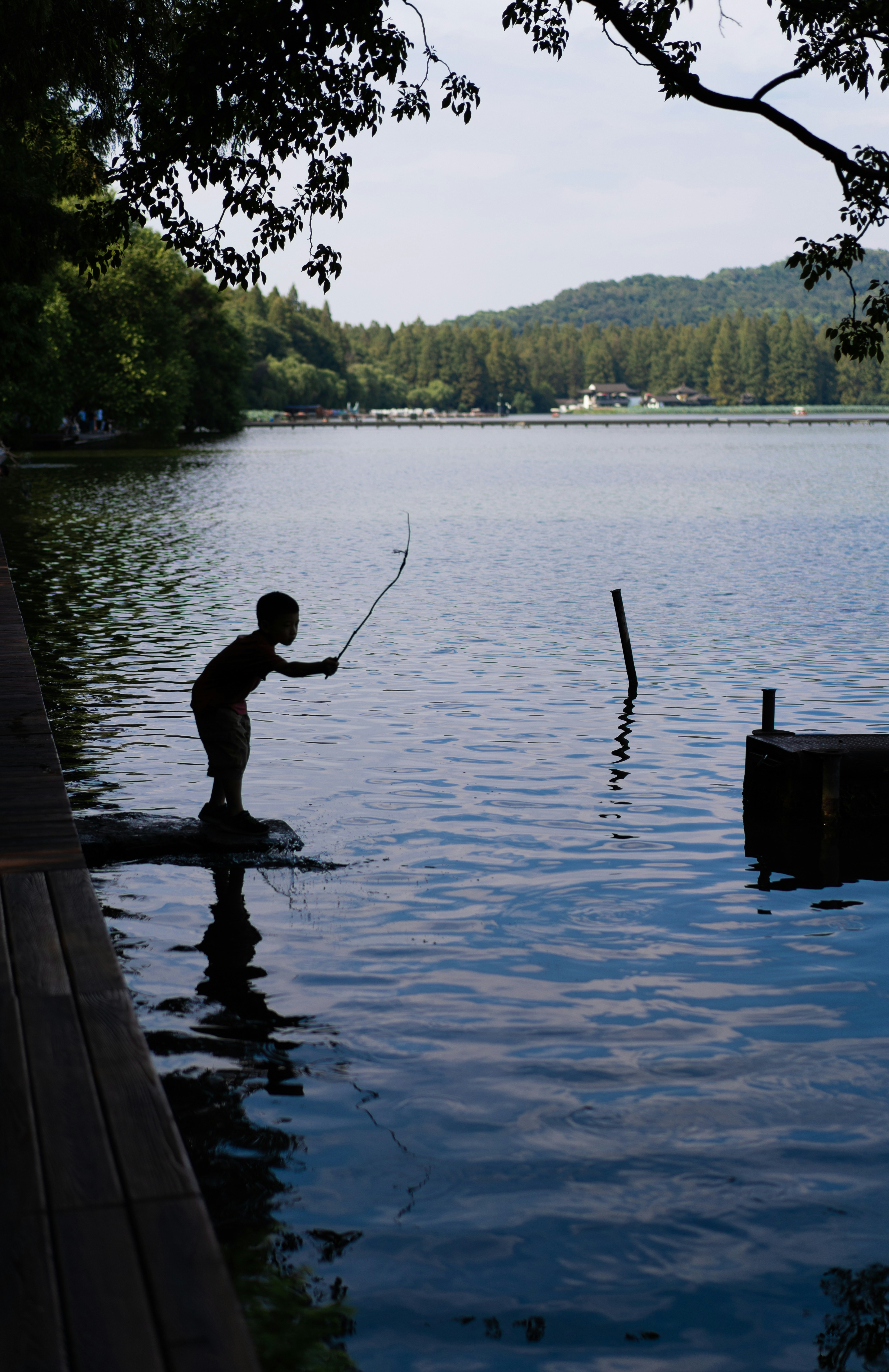 Silhouette of a boy fishing by a lake