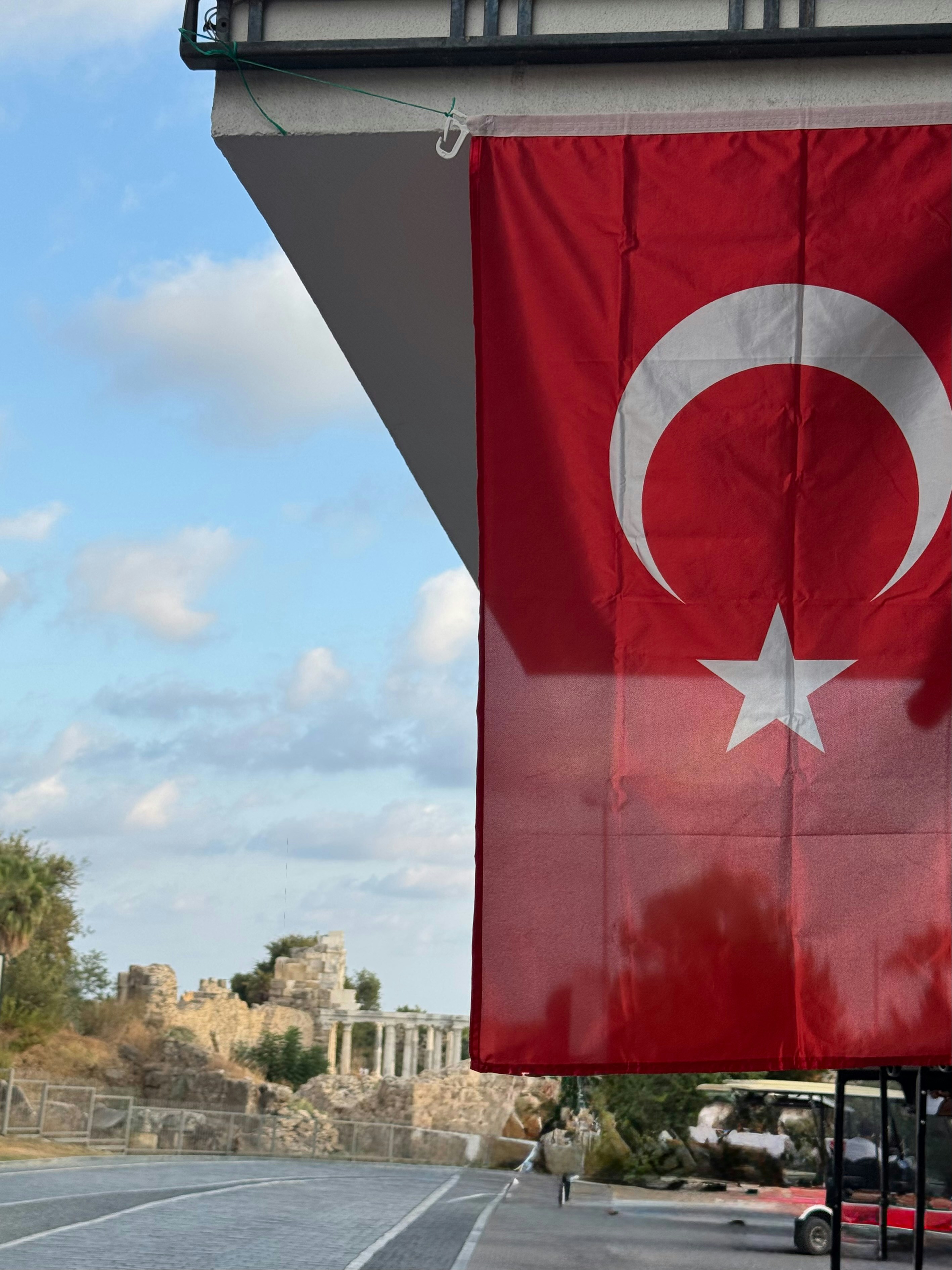 Crescent Banner Over Ruins: A Balcony Flag Framing Sky and History