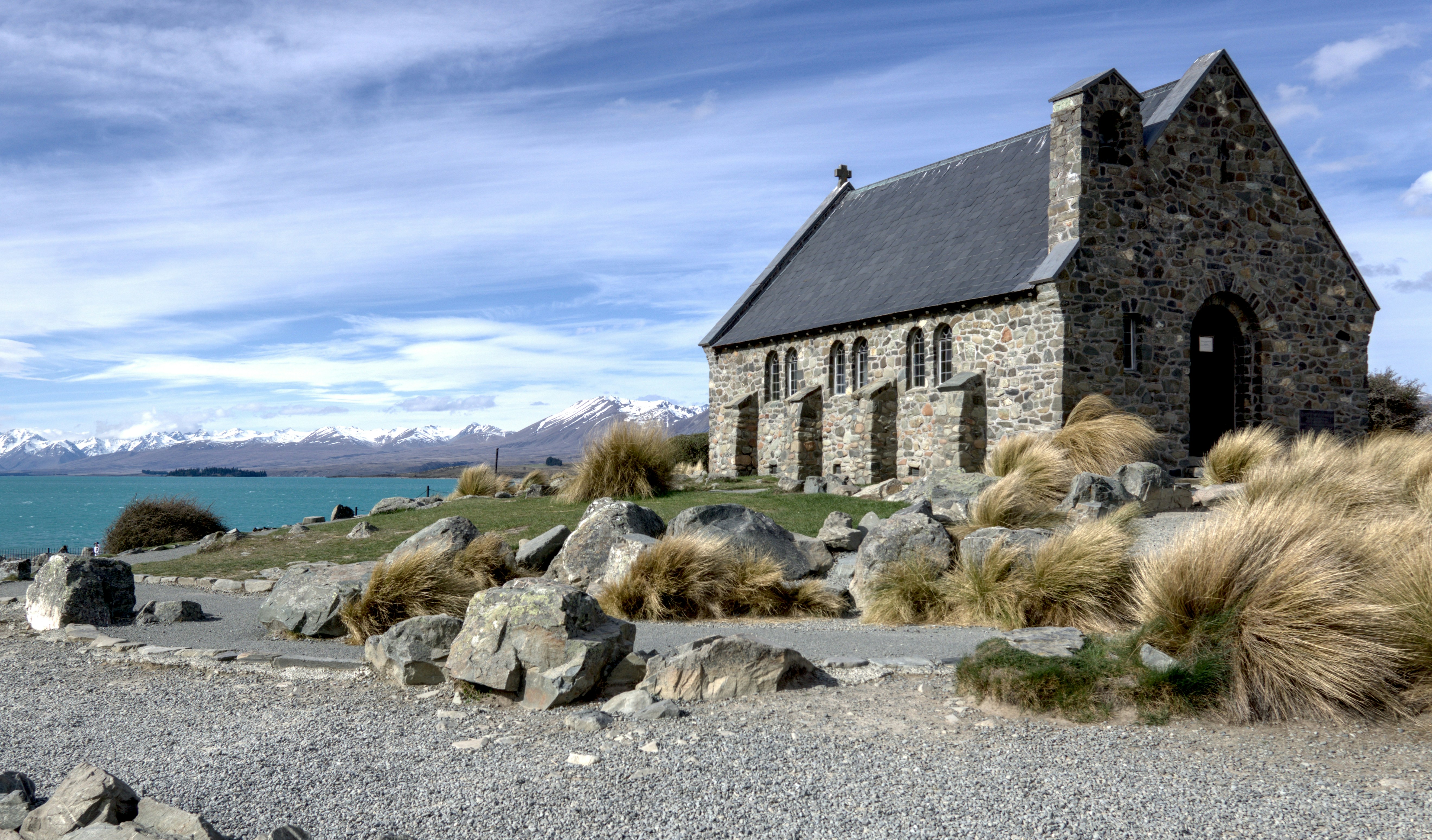 Stone church by a turquoise lake with mountains