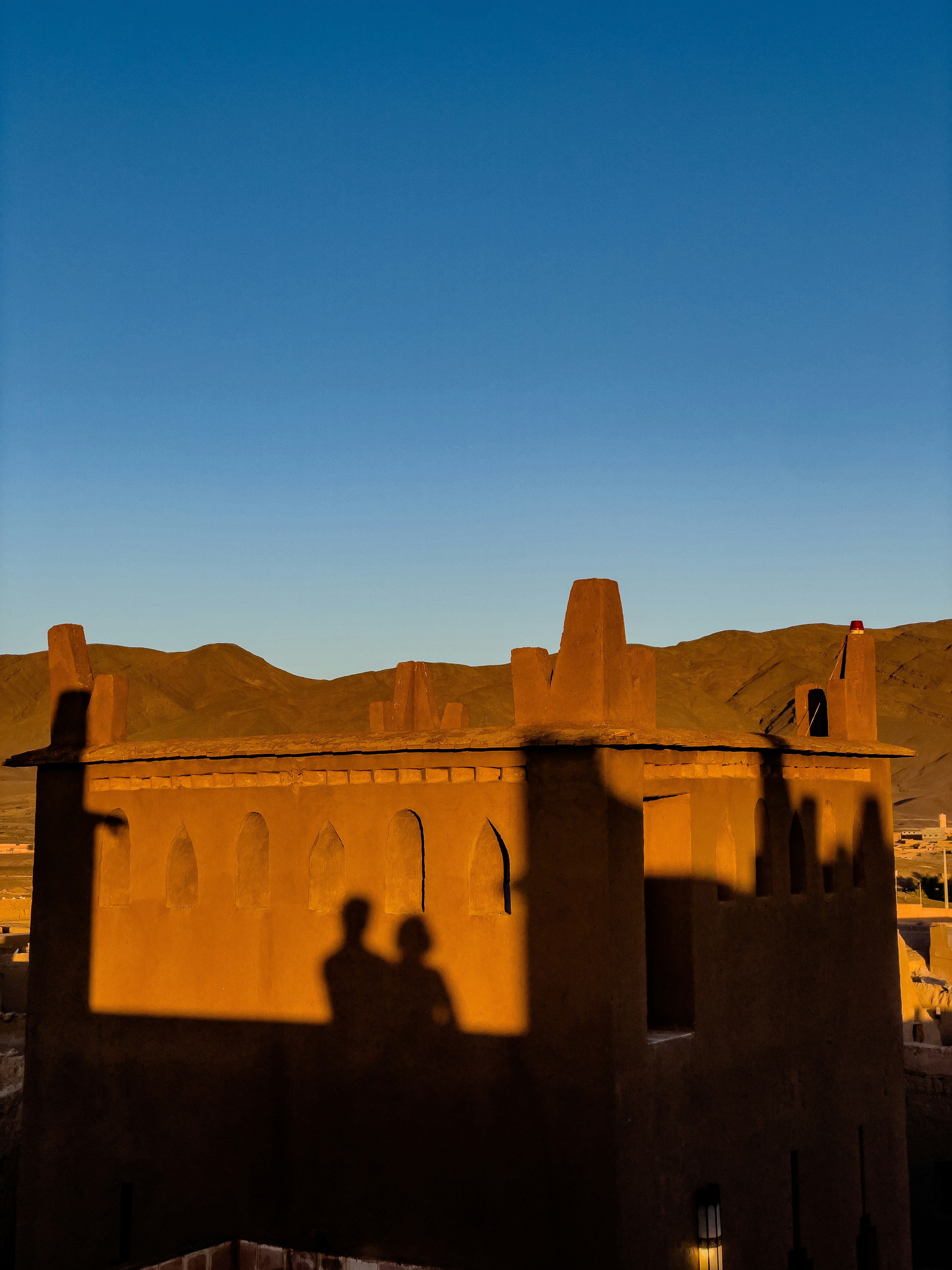 Silhouettes of a couple on a building at sunset.