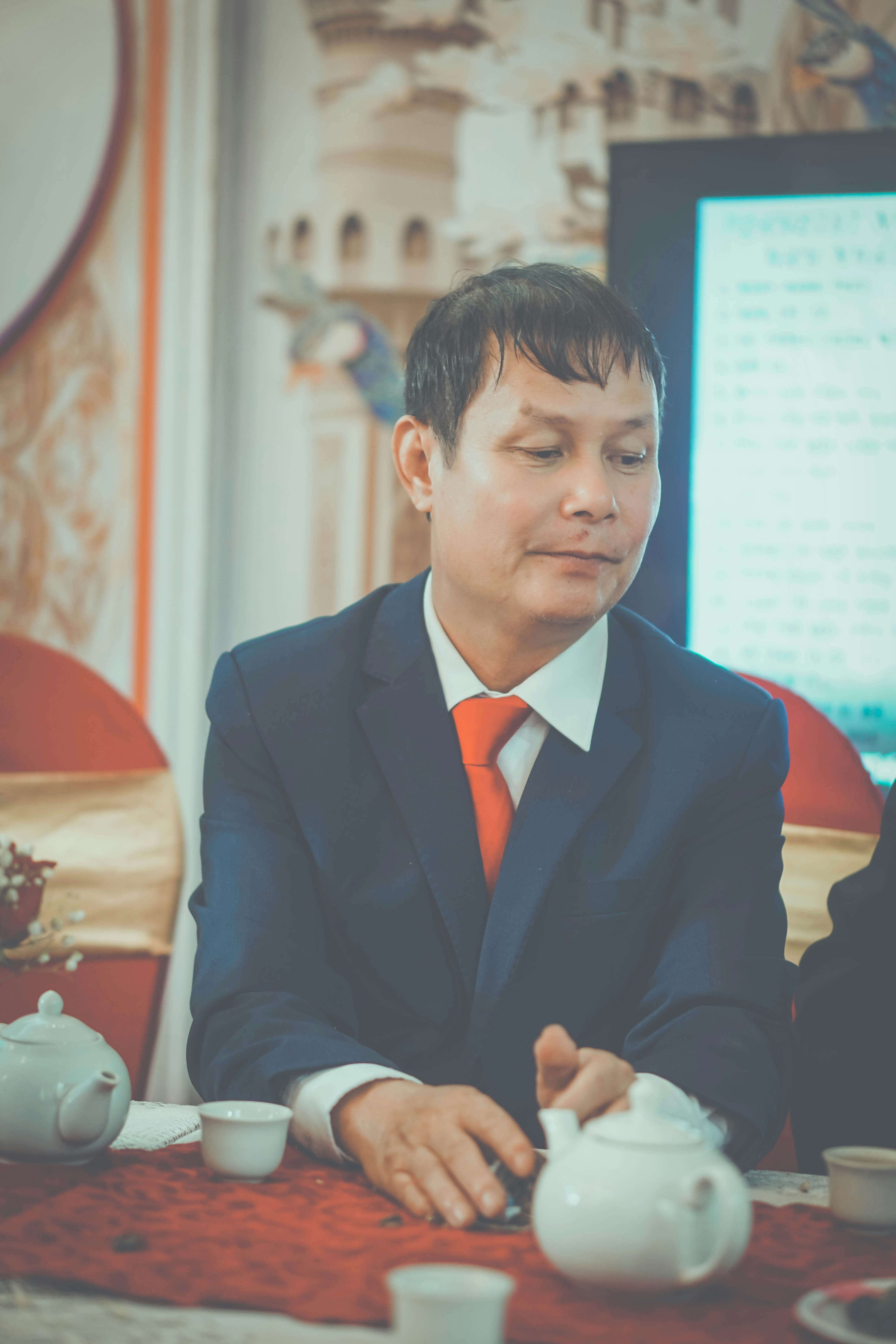Serene Focus at the Formal Table: A Man in a Red Tie with Tea