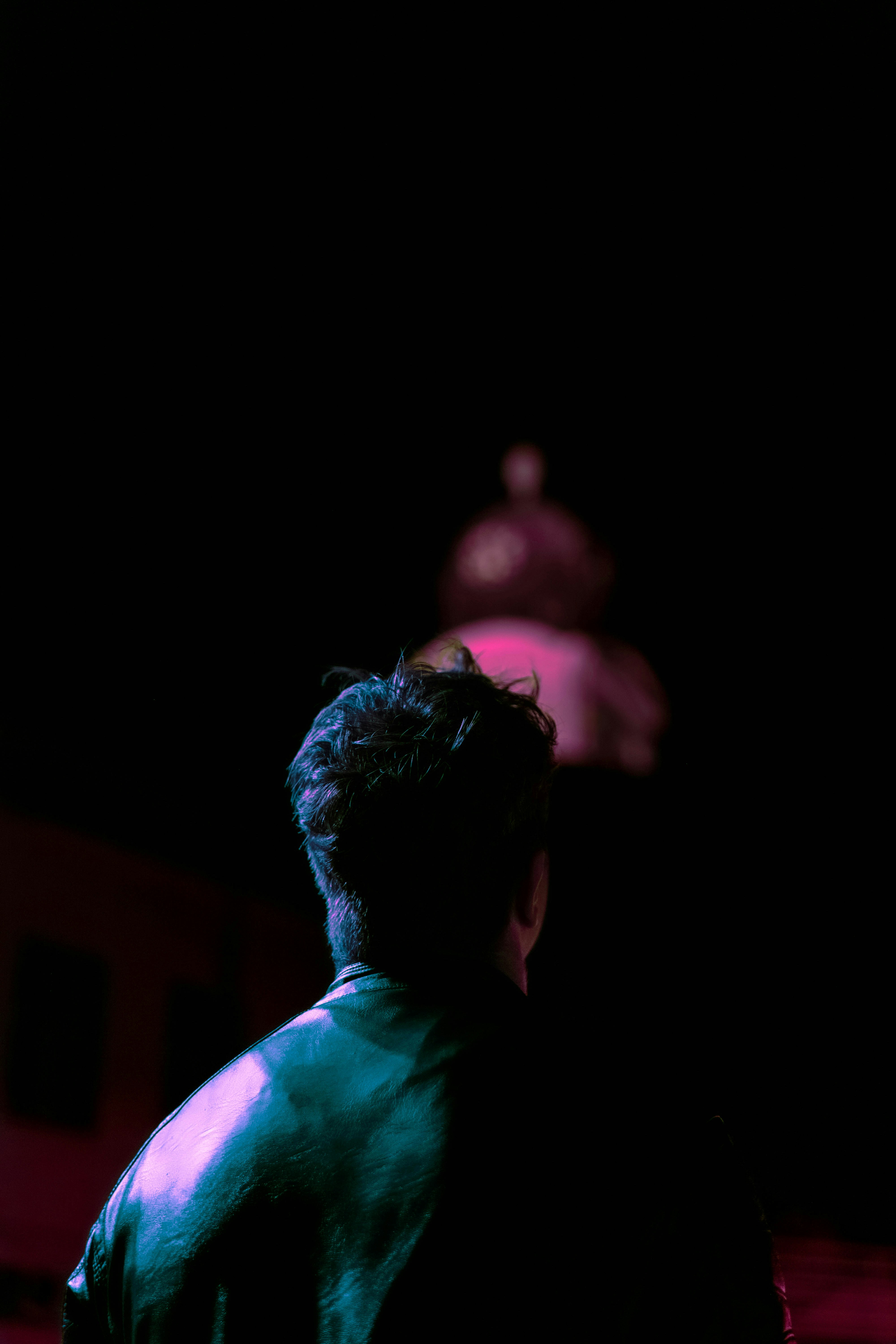 Teal-Glow Portrait: A Back-Facing Figure Amid a Pink-Illuminated Night Scene