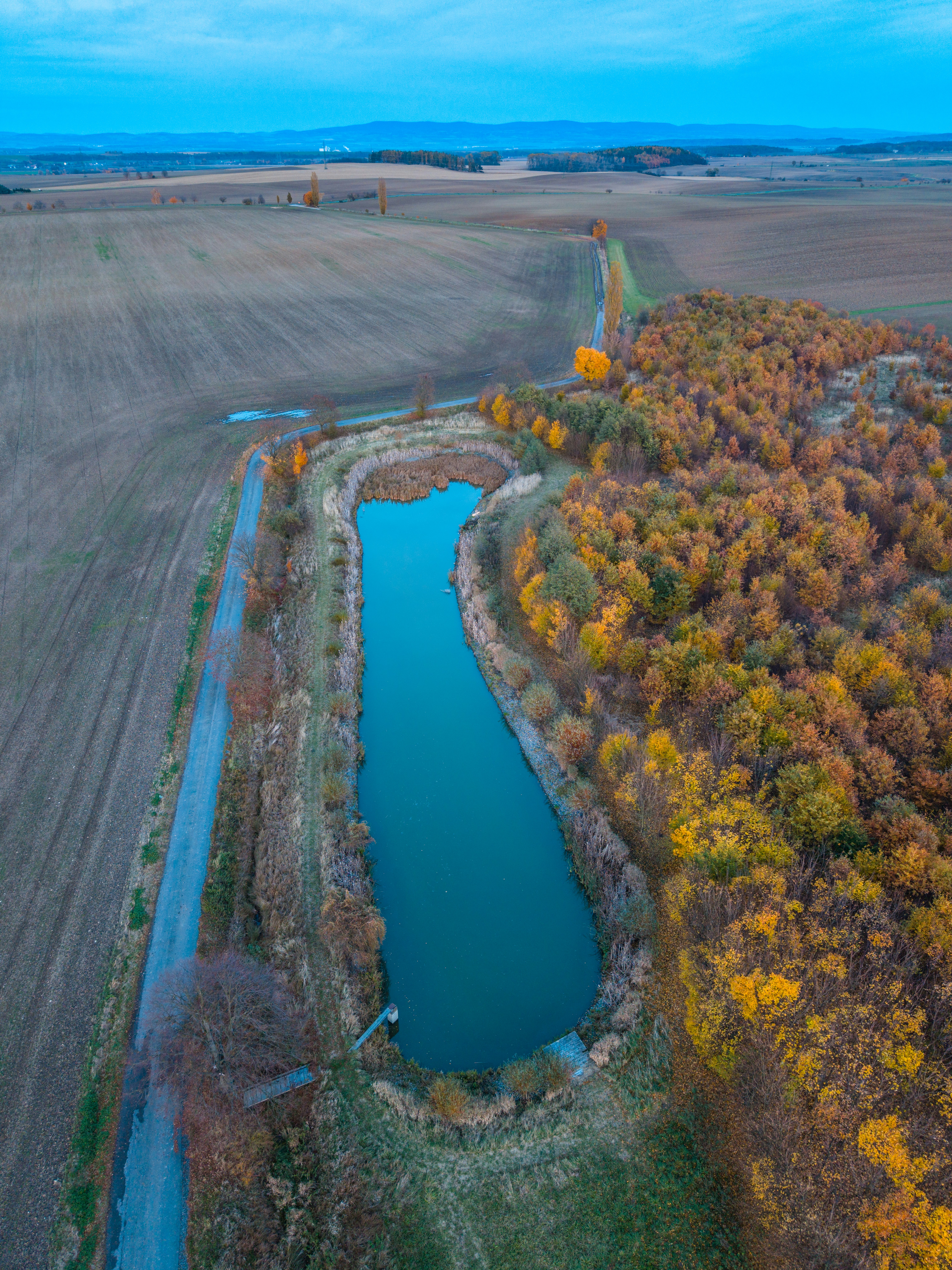 A winding waterway bordered by vibrant autumn foliage, showcasing a tranquil landscape. The scene captures the essence of fall with a mix of golden and green hues.
