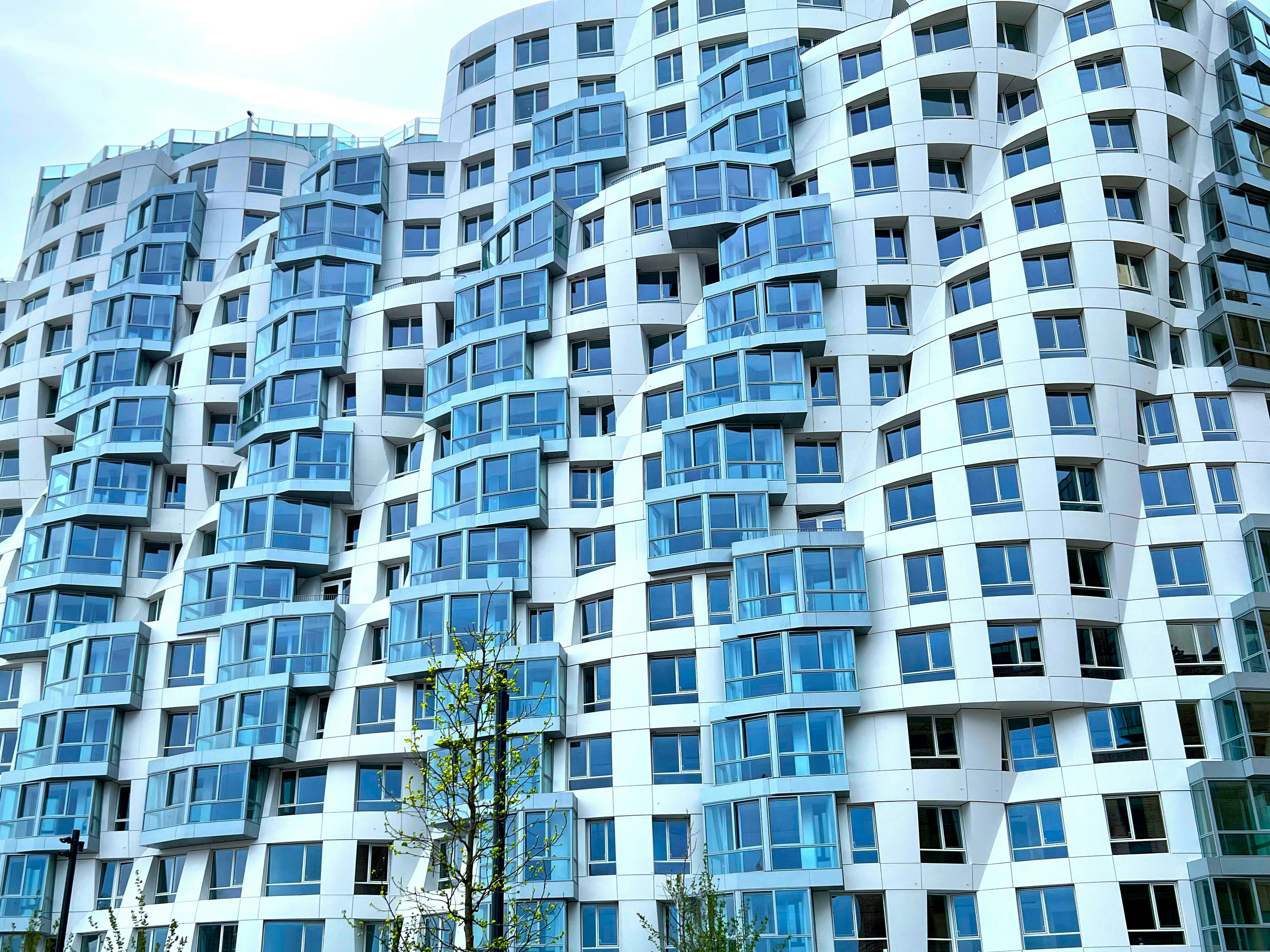 Wave-Windows | Modern white apartment building with blue glass balconies