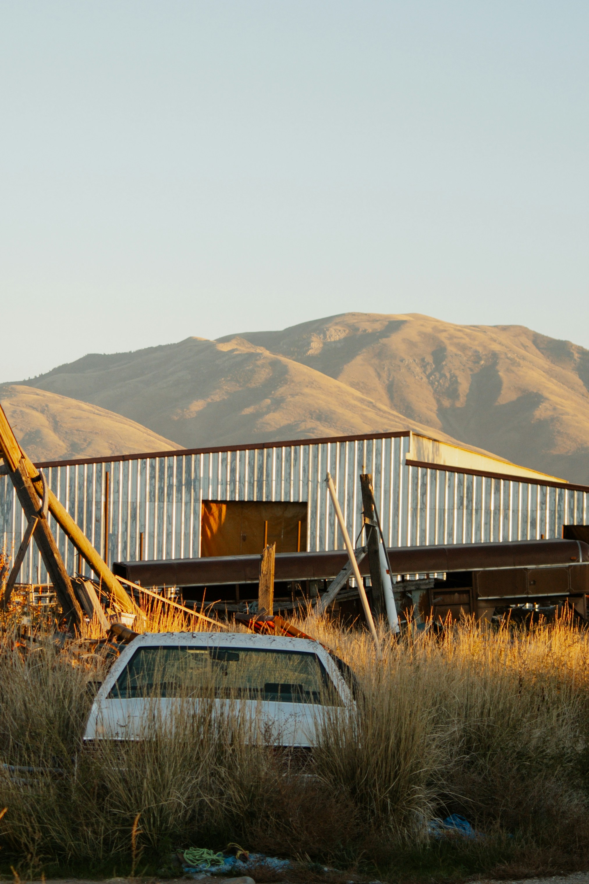 Sunlit Relic: An Abandoned Car Framed by a Weathered Shed at Dune Ridge
