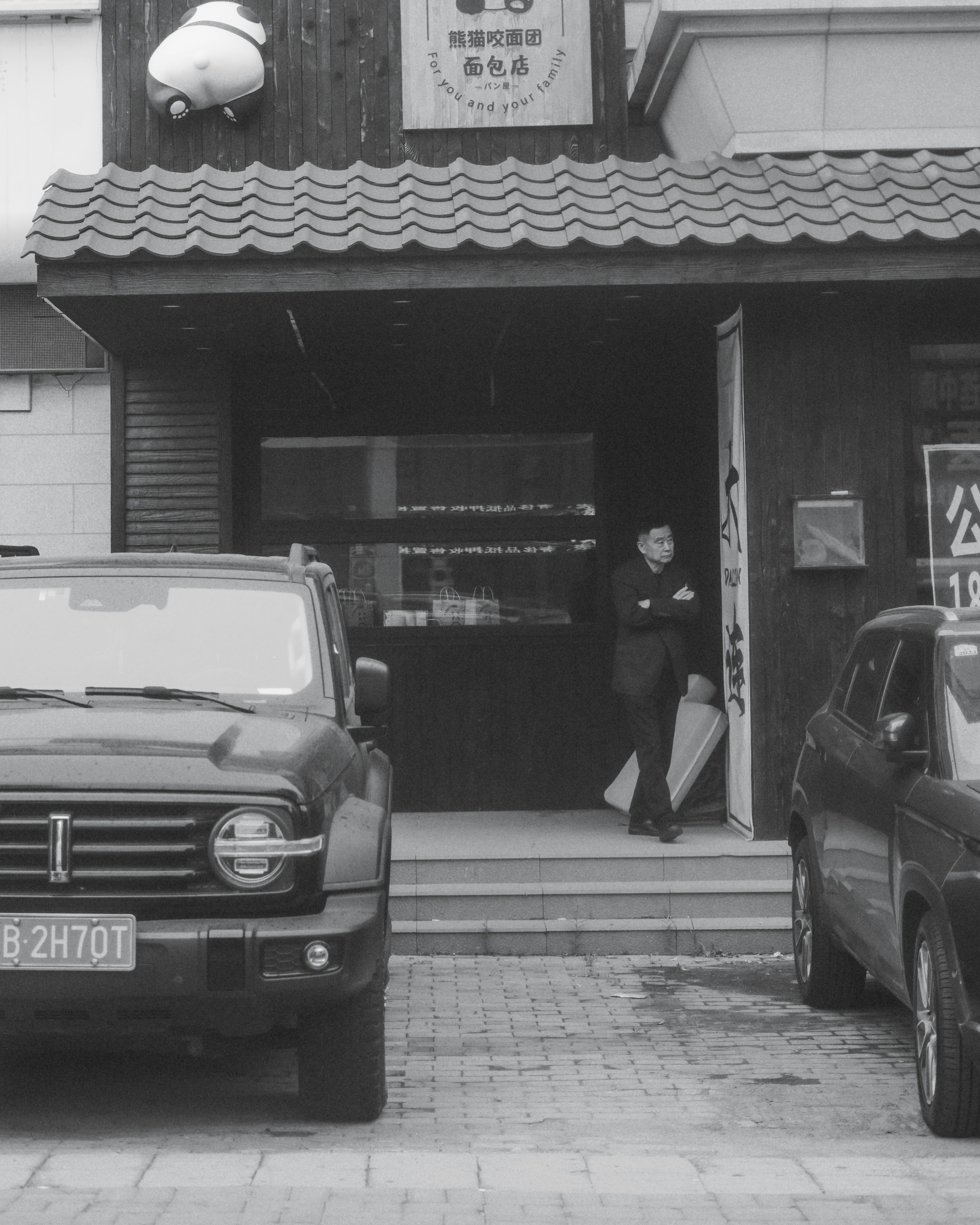 Man in Dark Suit at the Entrance: Quiet Moment Beneath a Tiled Roof