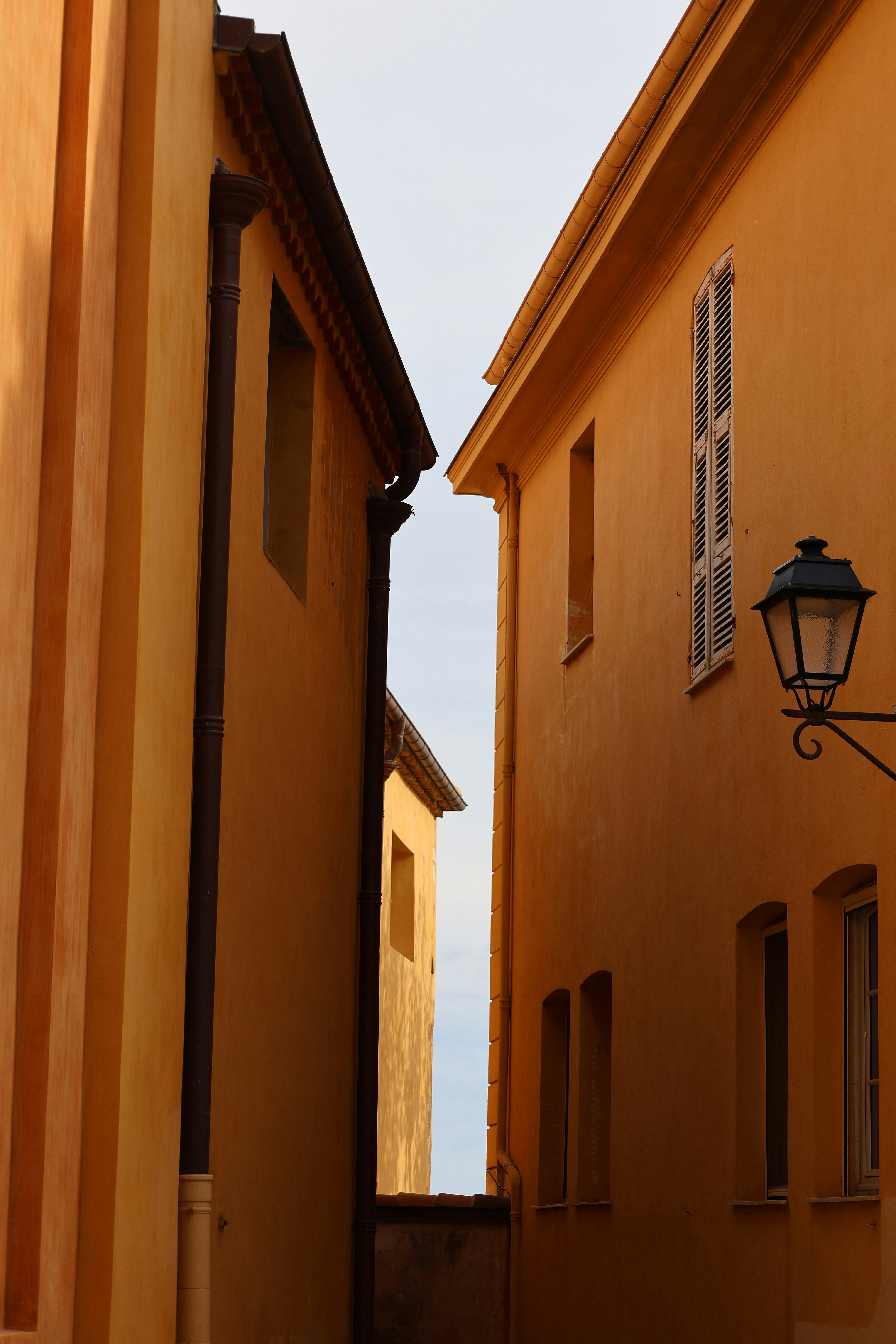 Beautiful yellow buildings in the south of France. | Two orange buildings with a street lamp.