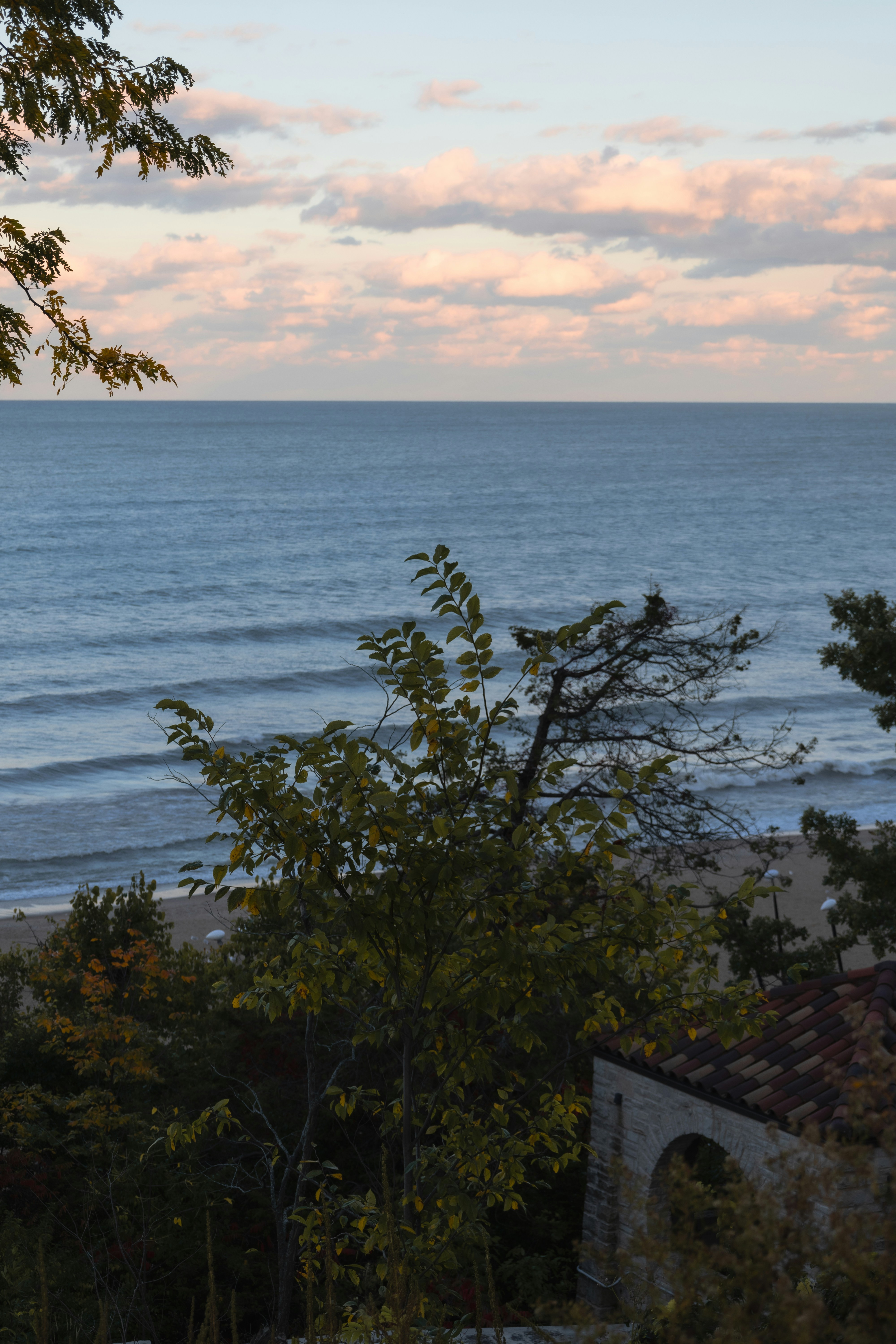 Ocean waves roll onto a sandy beach under clouds.