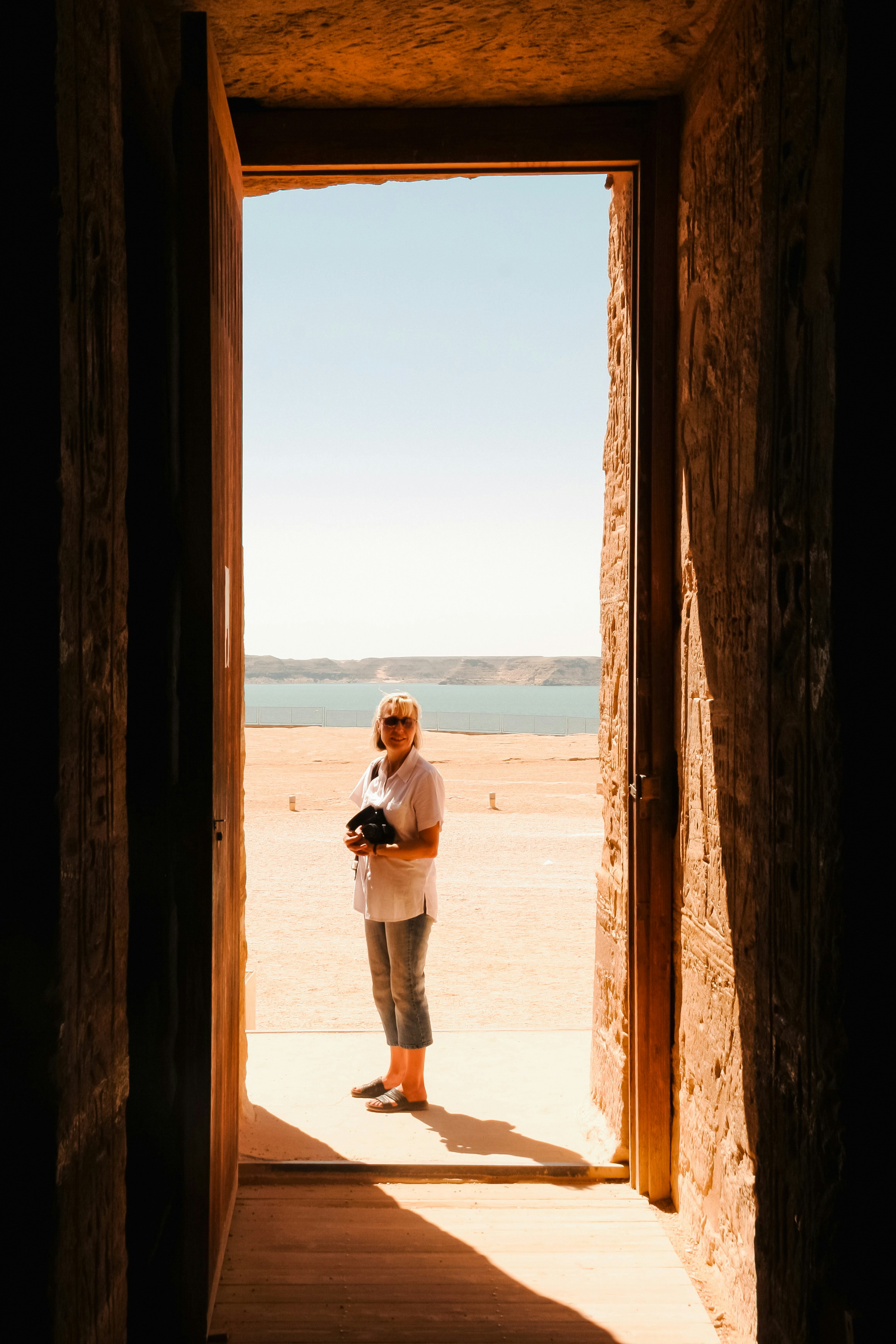 Threshold of Light: A Beach Portrait Framed by Stone Doors
