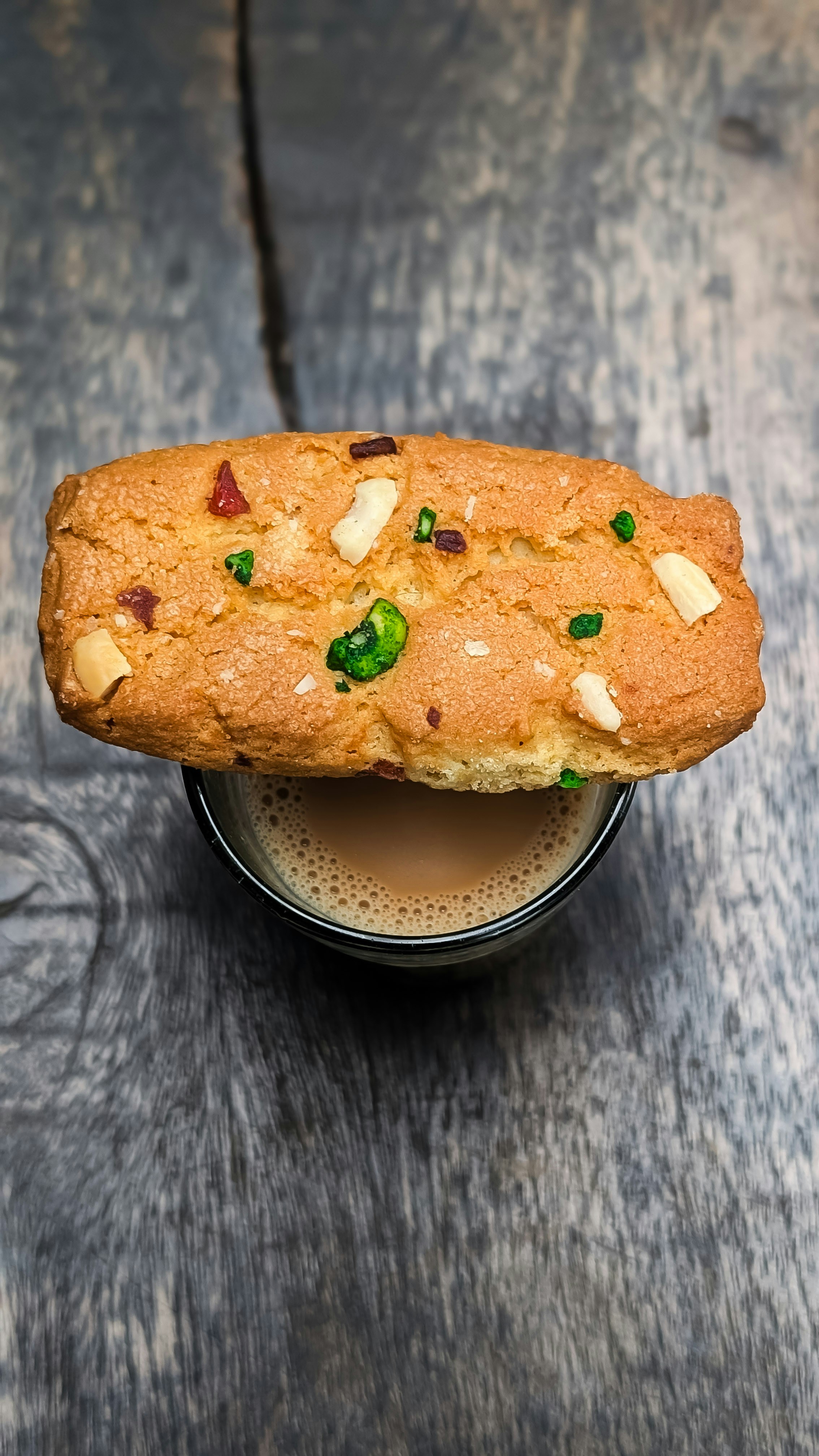 A biscuit with colorful fruit pieces on top of tea.