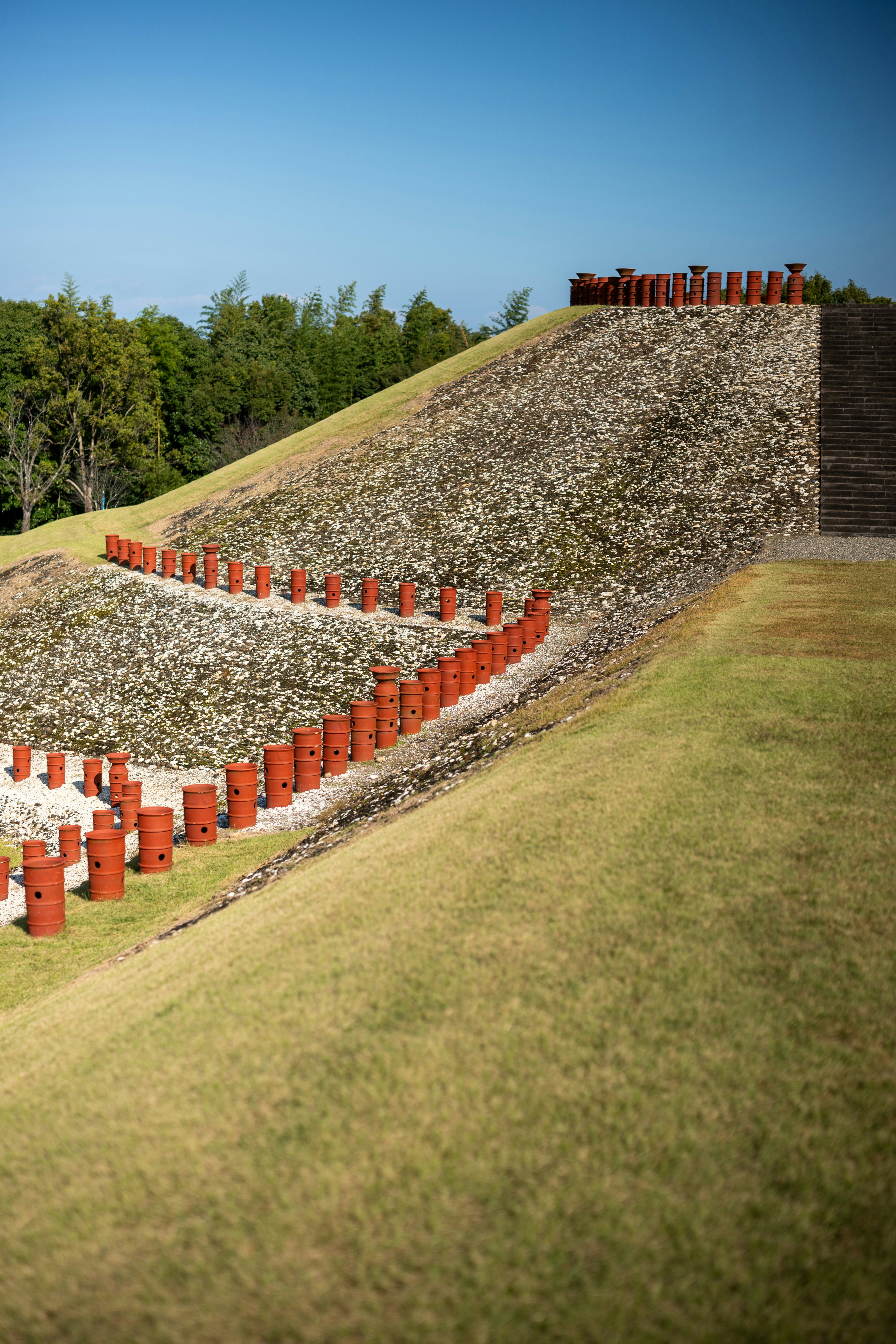 Ancient stone pyramid with red pillars and green grass