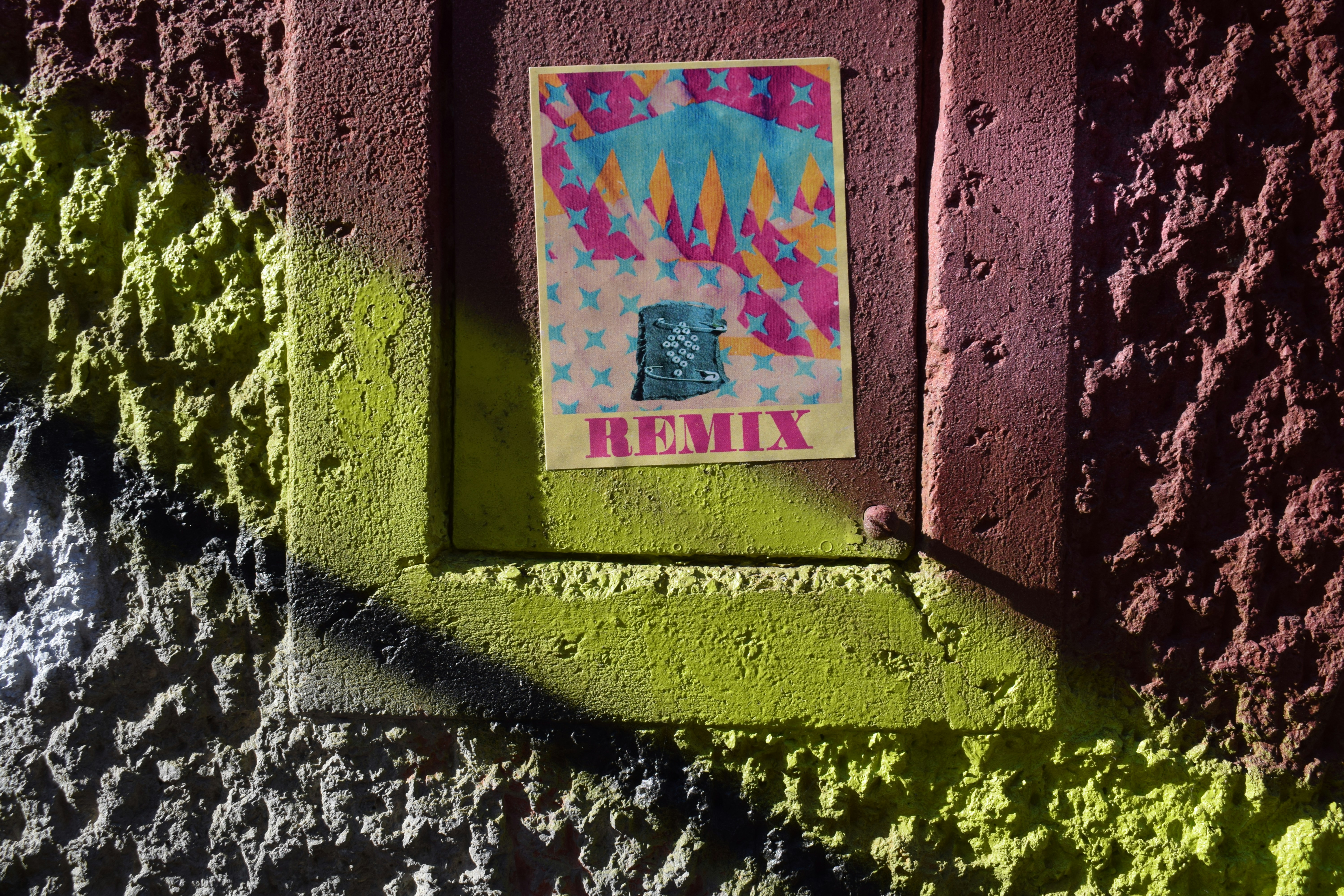 Vibrant poster titled 'REMIX' affixed to a textured wall, surrounded by graffiti and paint splashes.