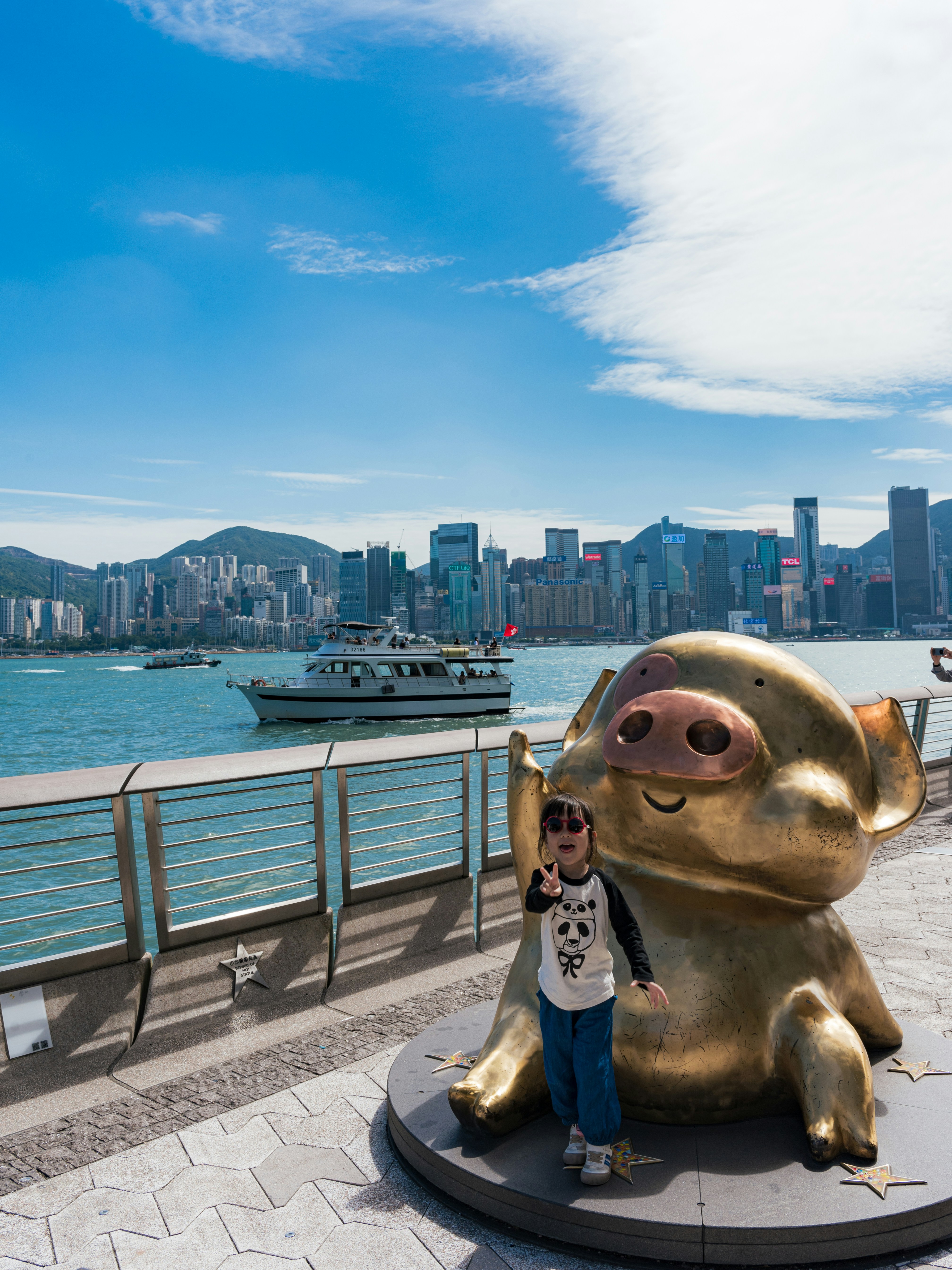 Gilded Pig by the Promenade: A Child's Joy Against Kowloon Skyline