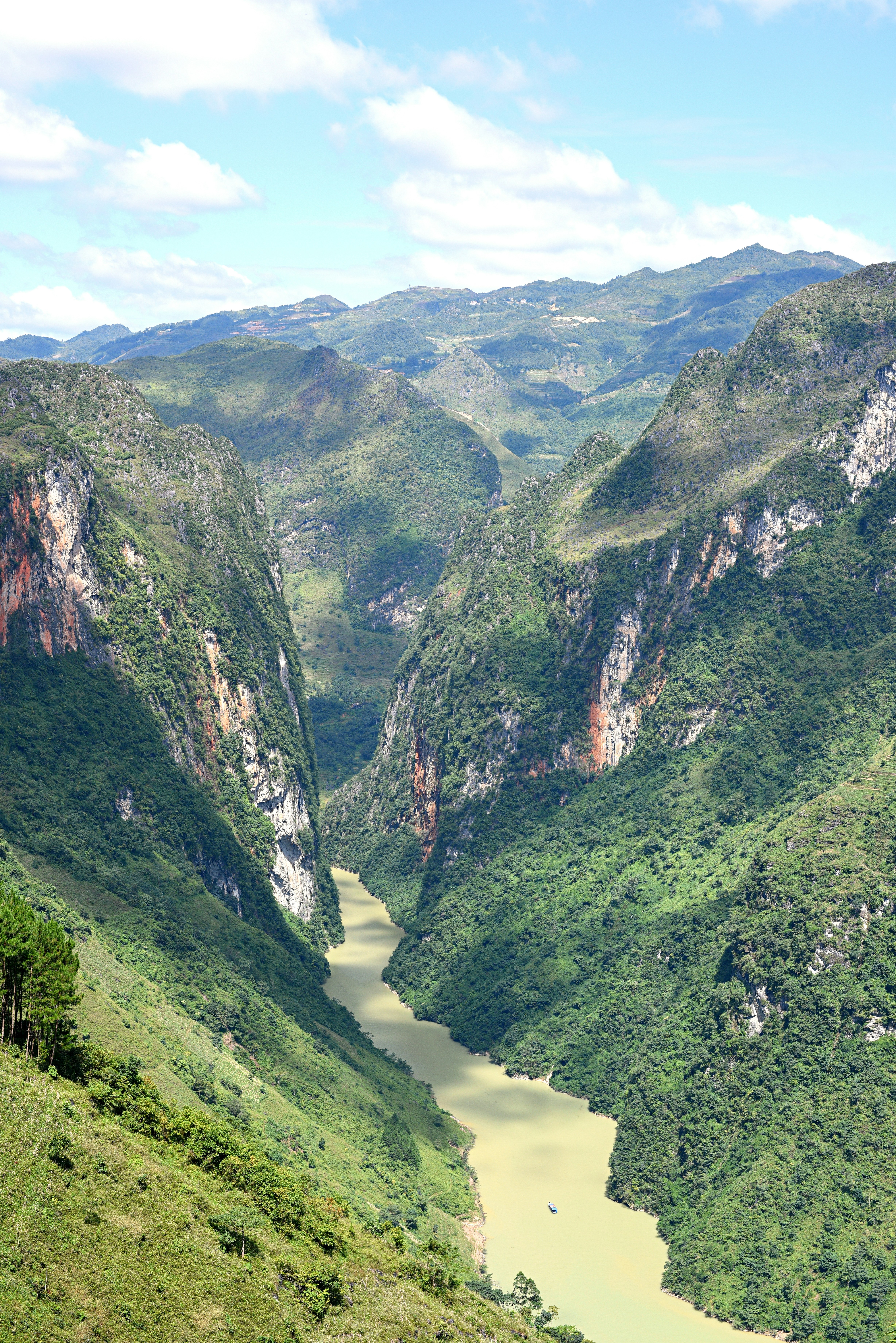 https://amajourneyasia.com/northeast-vietnam-tour | A wide river flows through a lush green mountain valley.