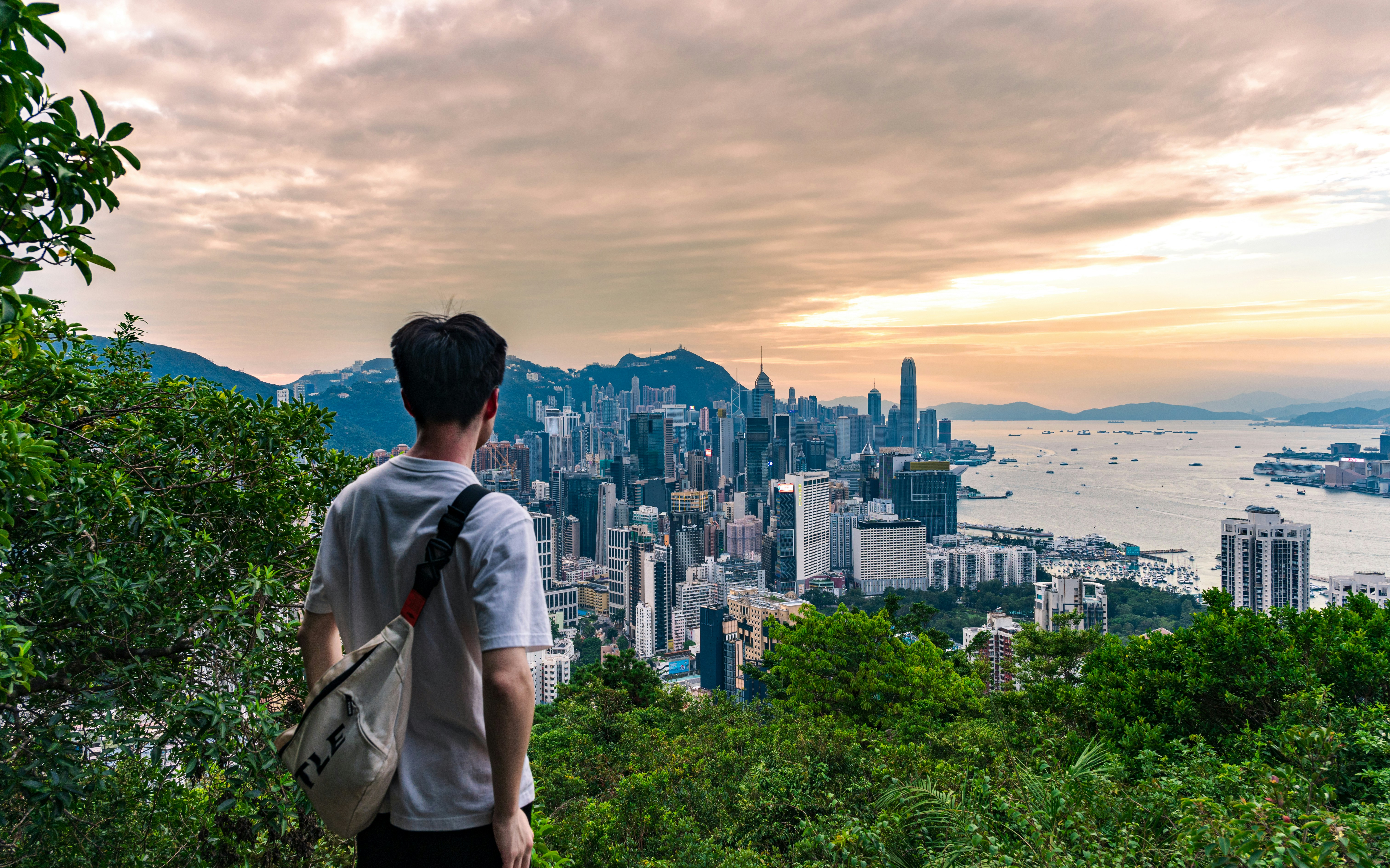 Hombre con vistas al horizonte de Hong Kong desde una exuberante colina ...