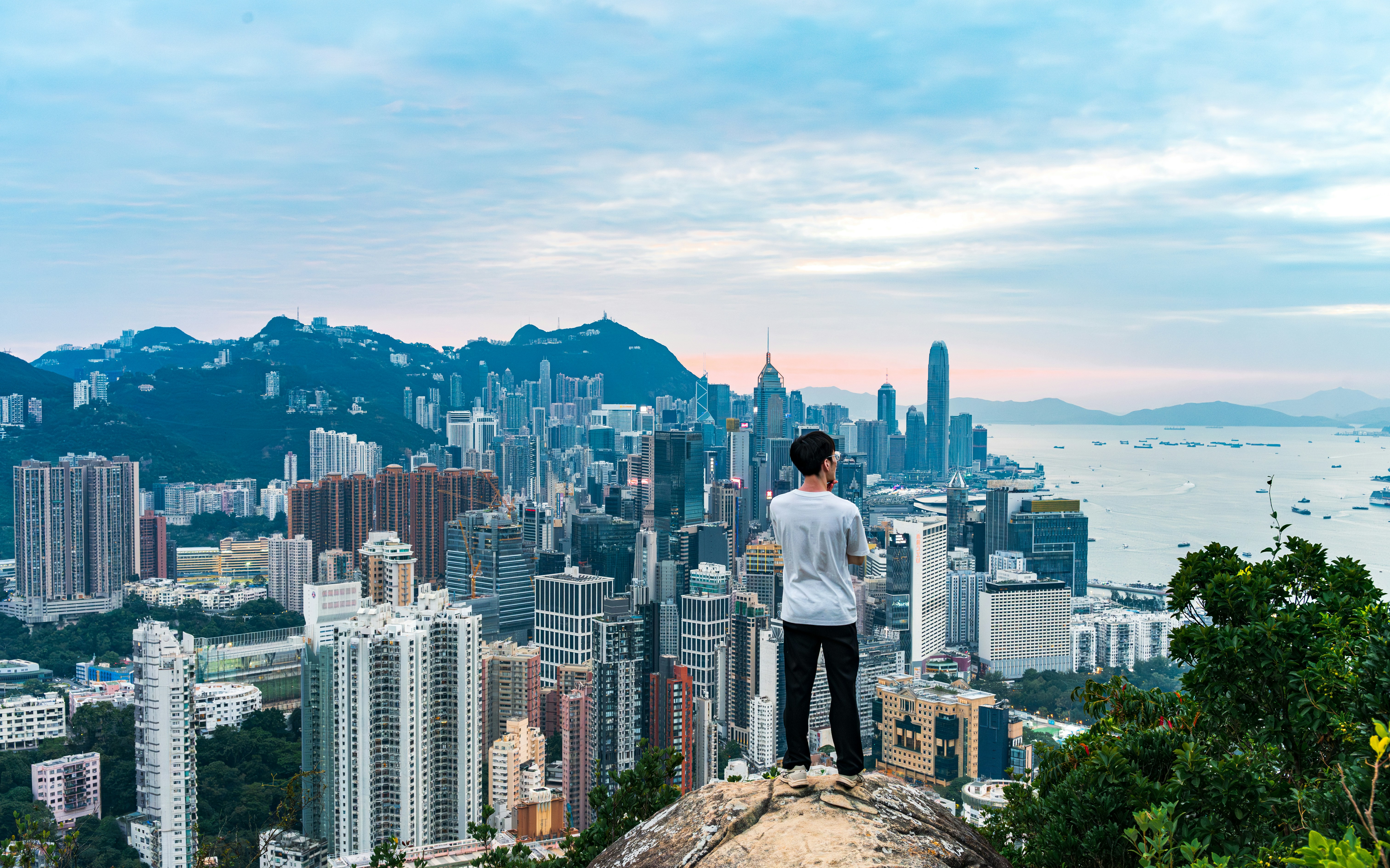 Hombre mirando el horizonte de una ciudad desde la cima de una colina ...