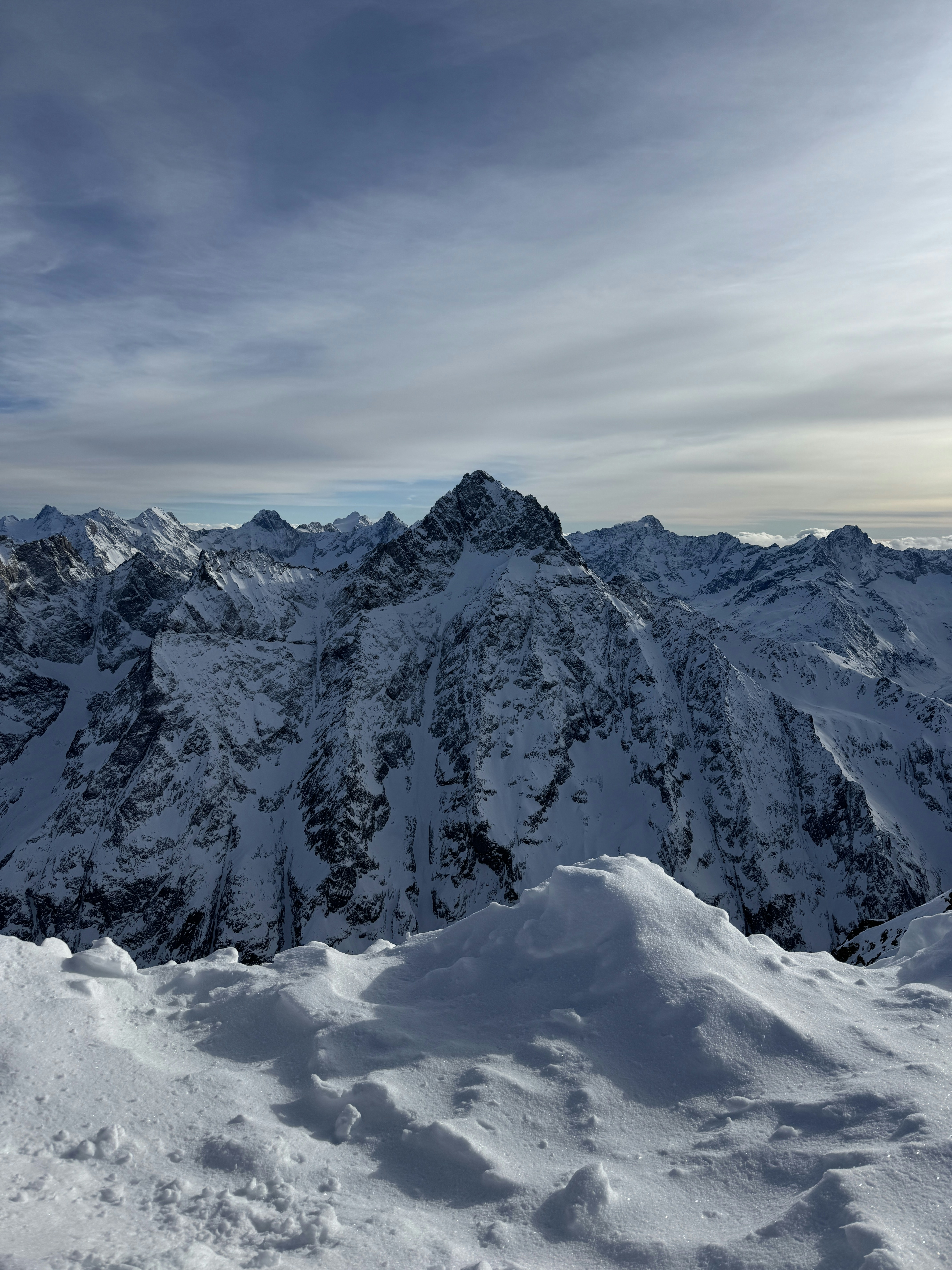Snow-covered mountain range with dramatic peaks and a serene sky, showcasing the beauty of winter landscapes.