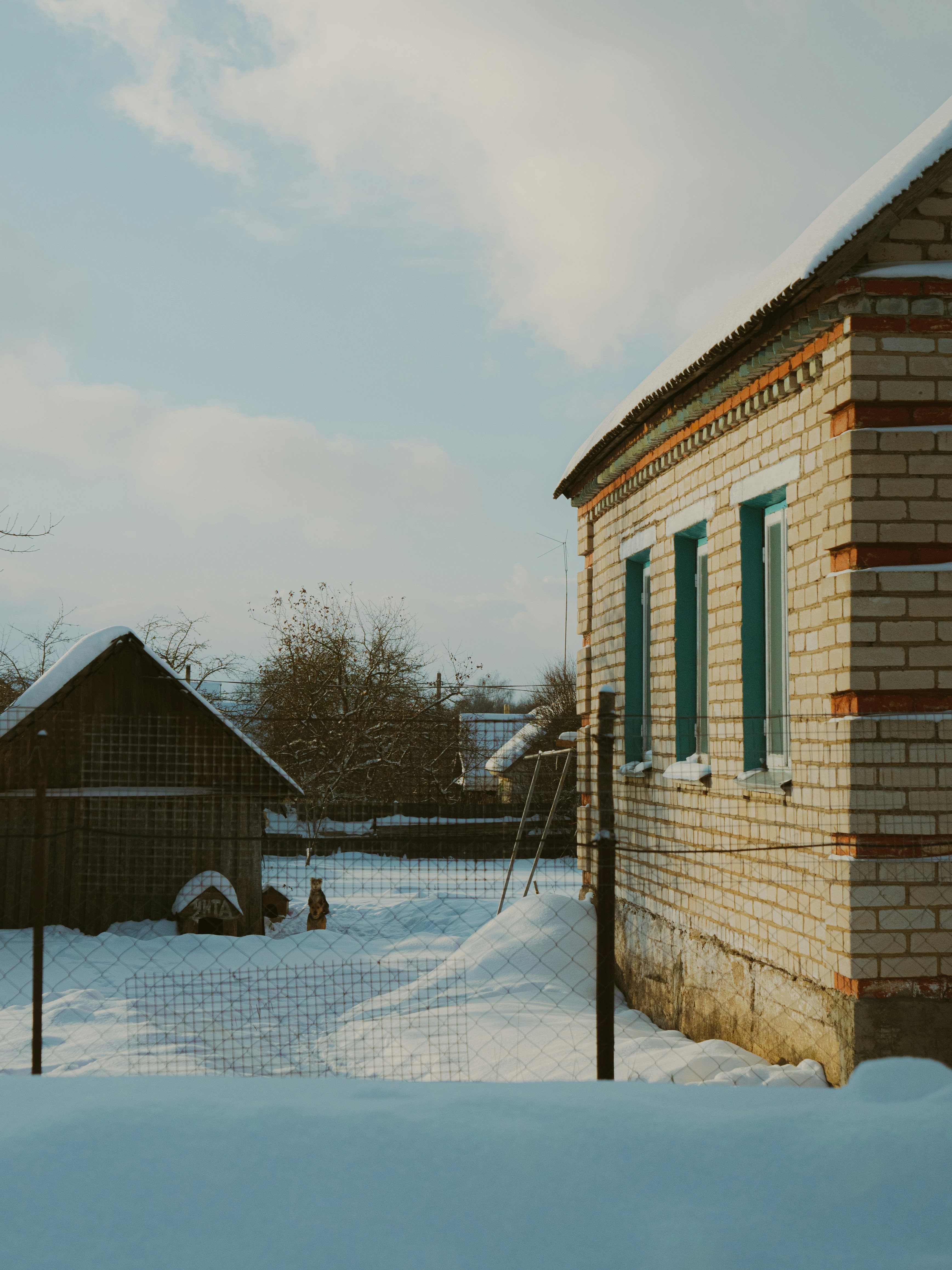 Sunlit Brick Corner: Winter Silence by a Snow-Laden Fence