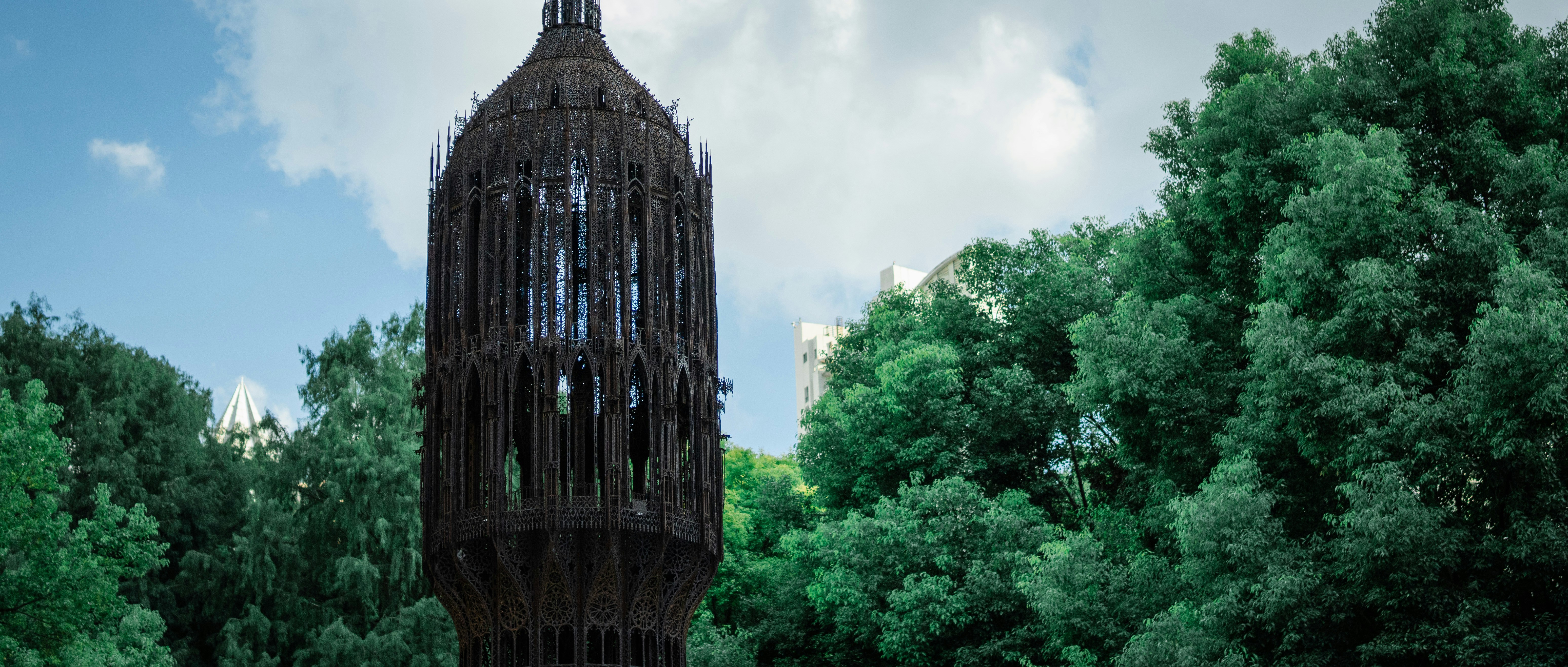 Iron Lattice Sentinel Rising Through Park Canopy