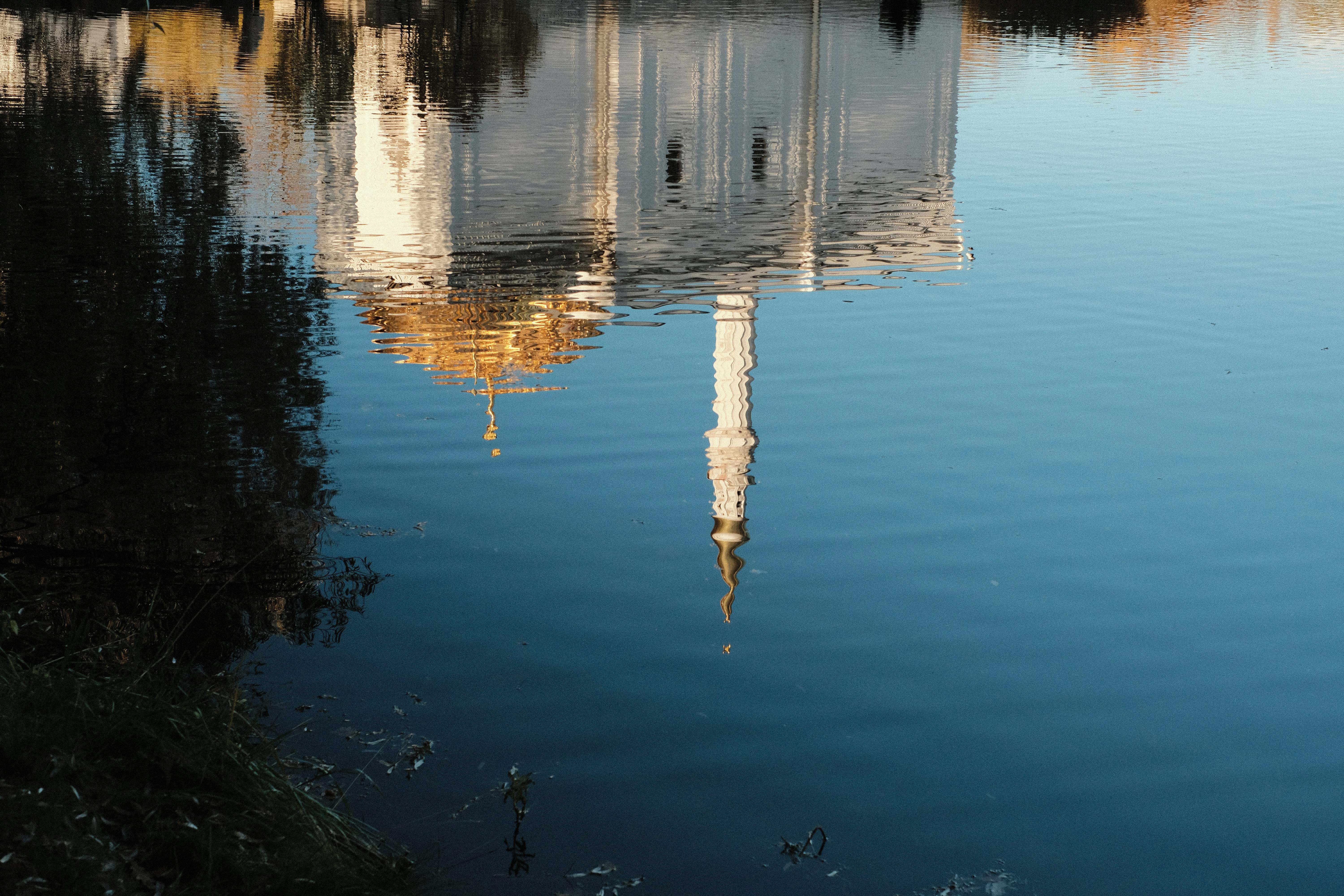 White building with golden dome reflected in water