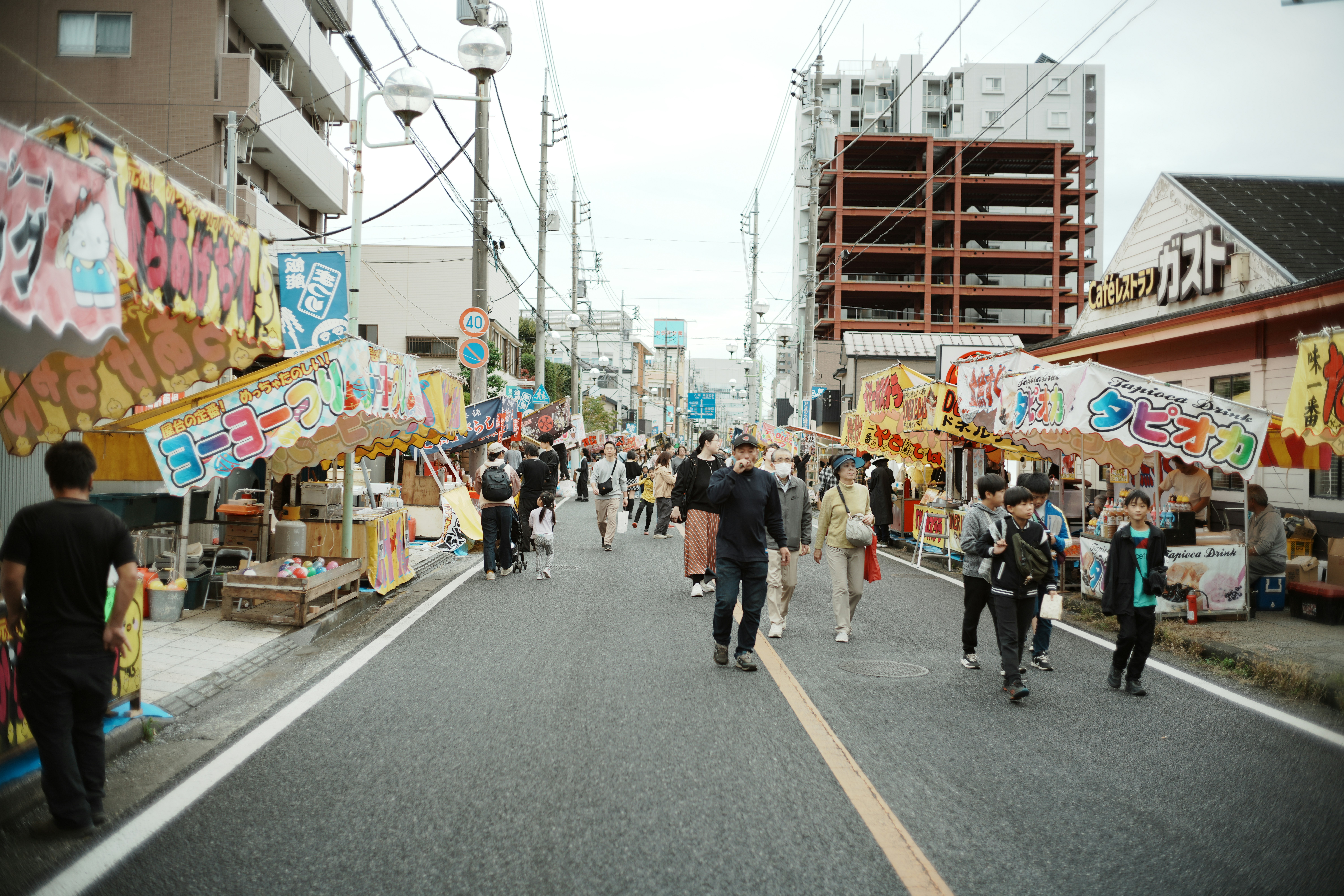 Busy street market scene adorned with colorful festival stalls and crowds of people enjoying the festivities.