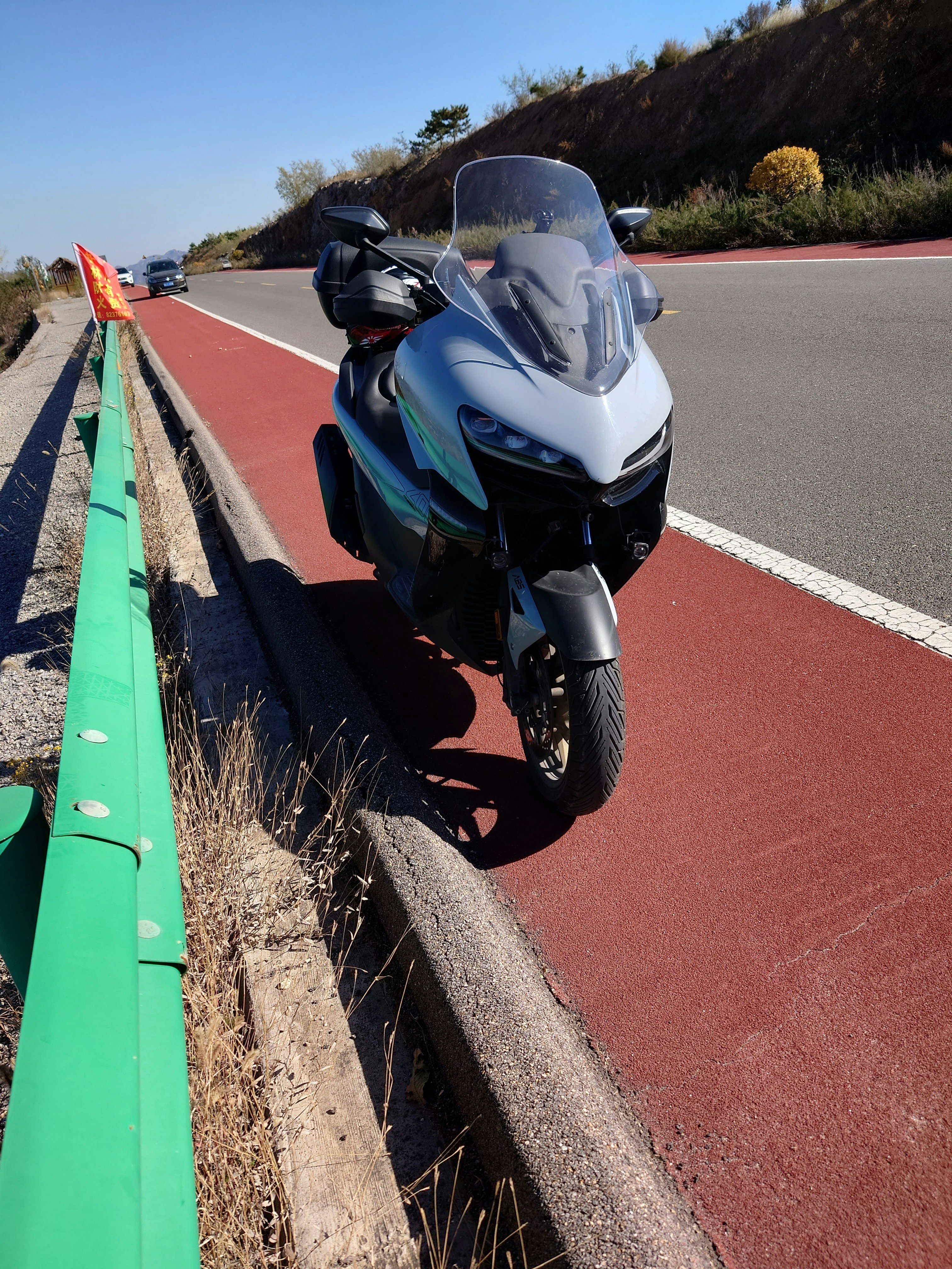 A silver scooter parked on a red path.