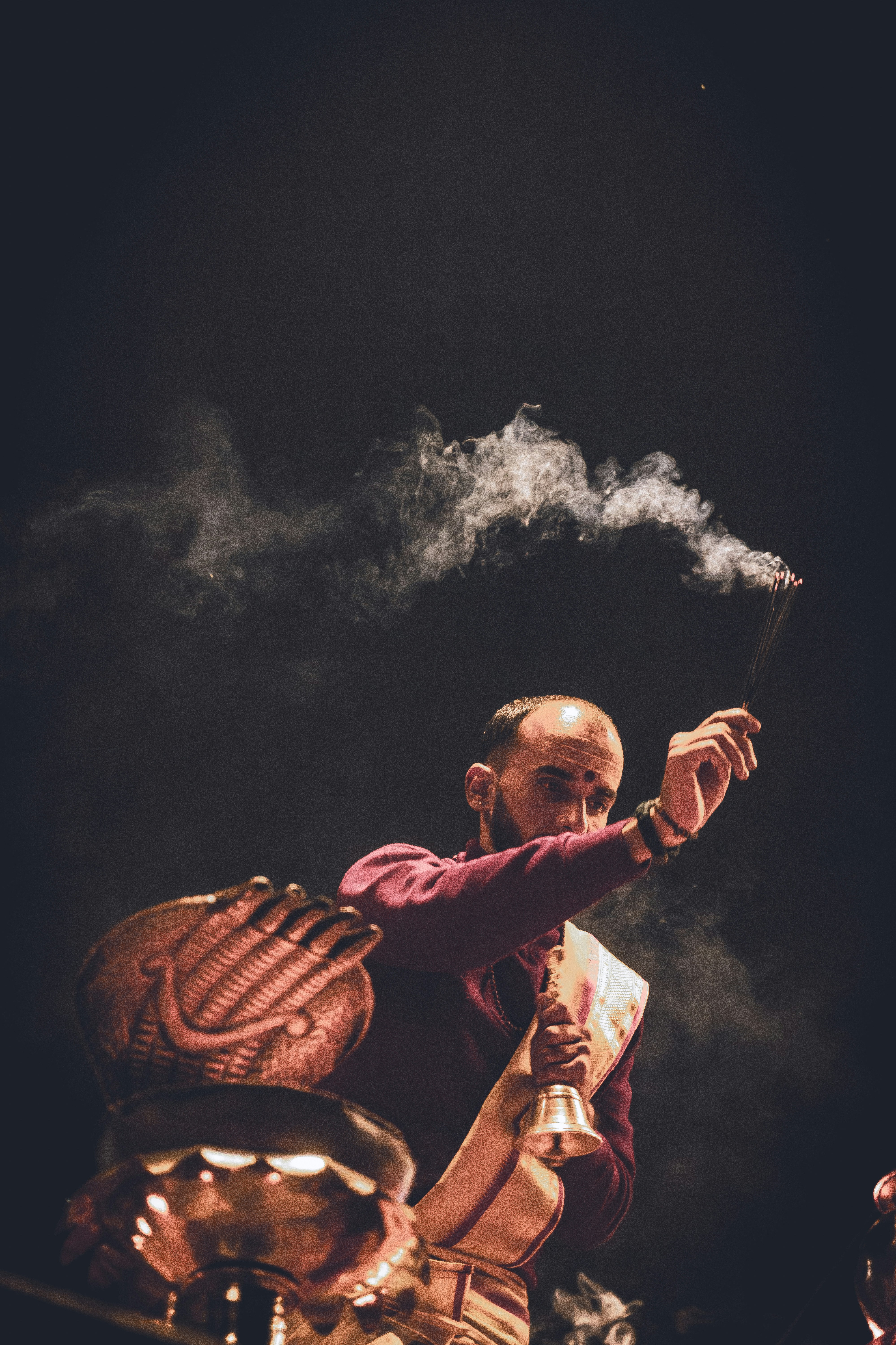 A man performing a ritual with incense, enveloped in smoke, showcasing a blend of spirituality and tradition.