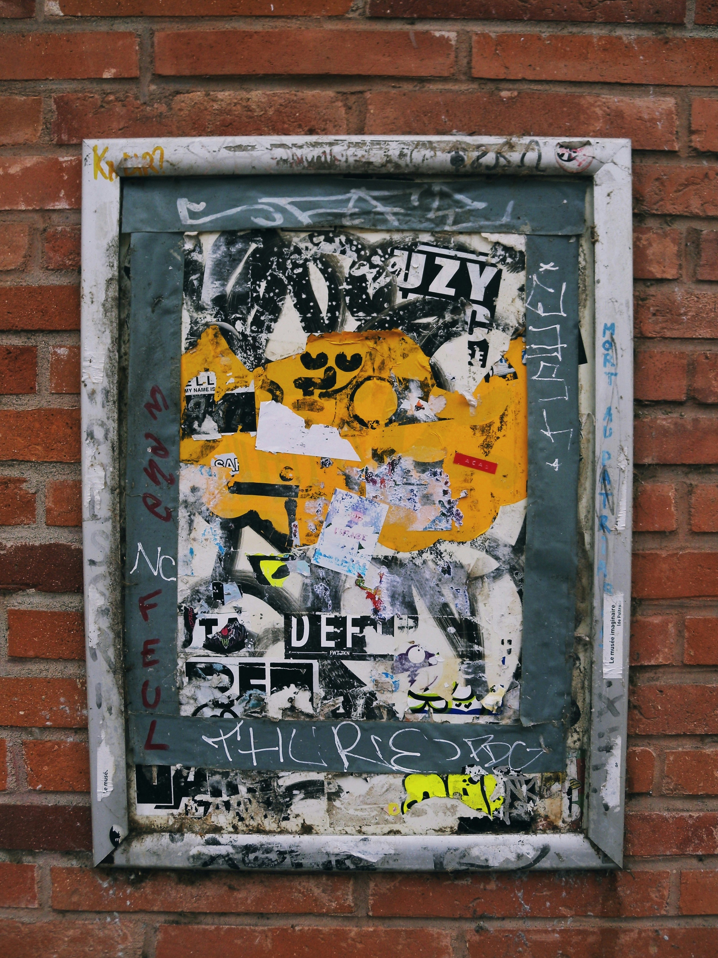 A collage of vibrant stickers and graffiti on a weathered frame against a brick wall, showcasing urban art's evolution. The piece reflects the dynamic nature of street culture.