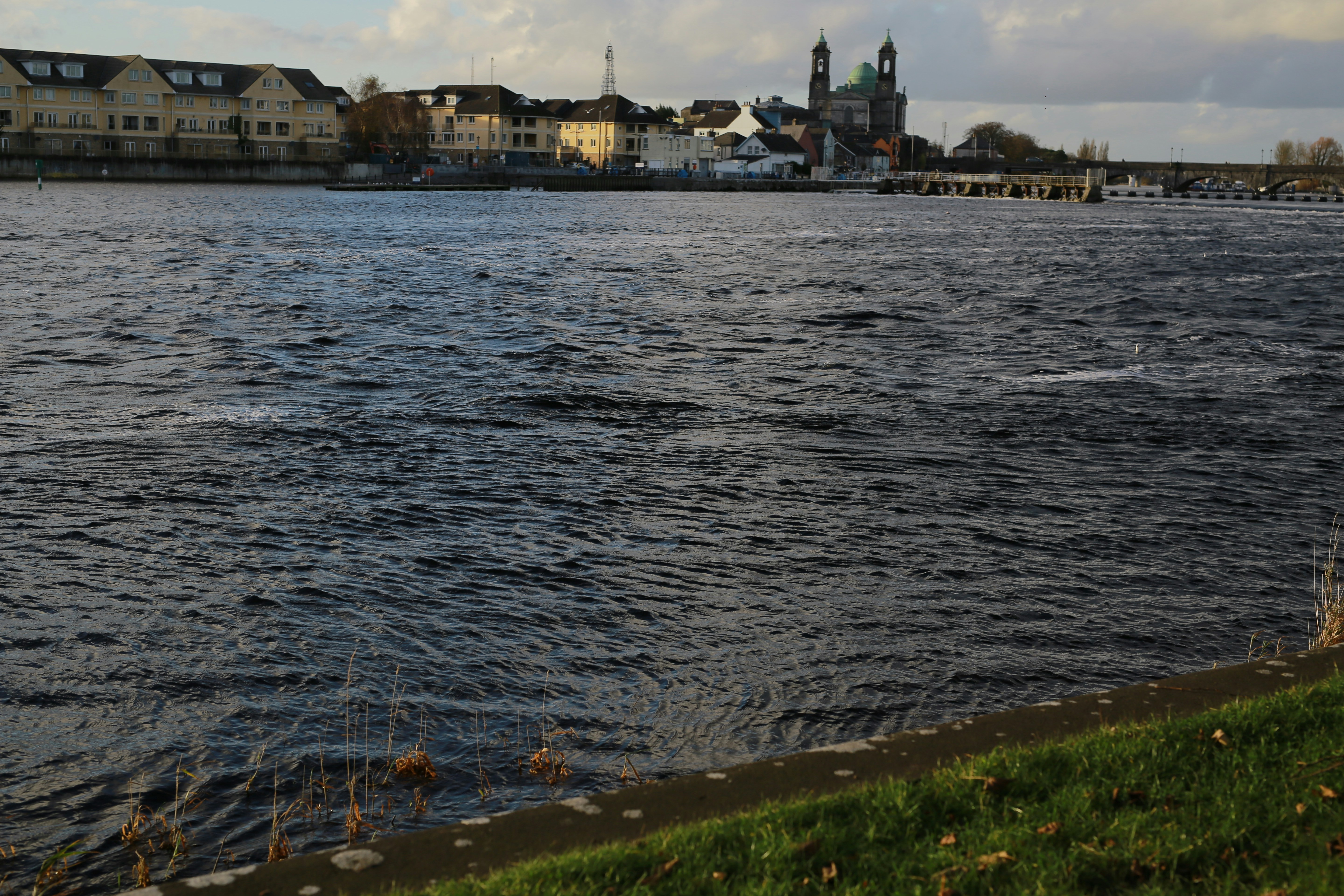 River flowing past buildings and bridge under sky