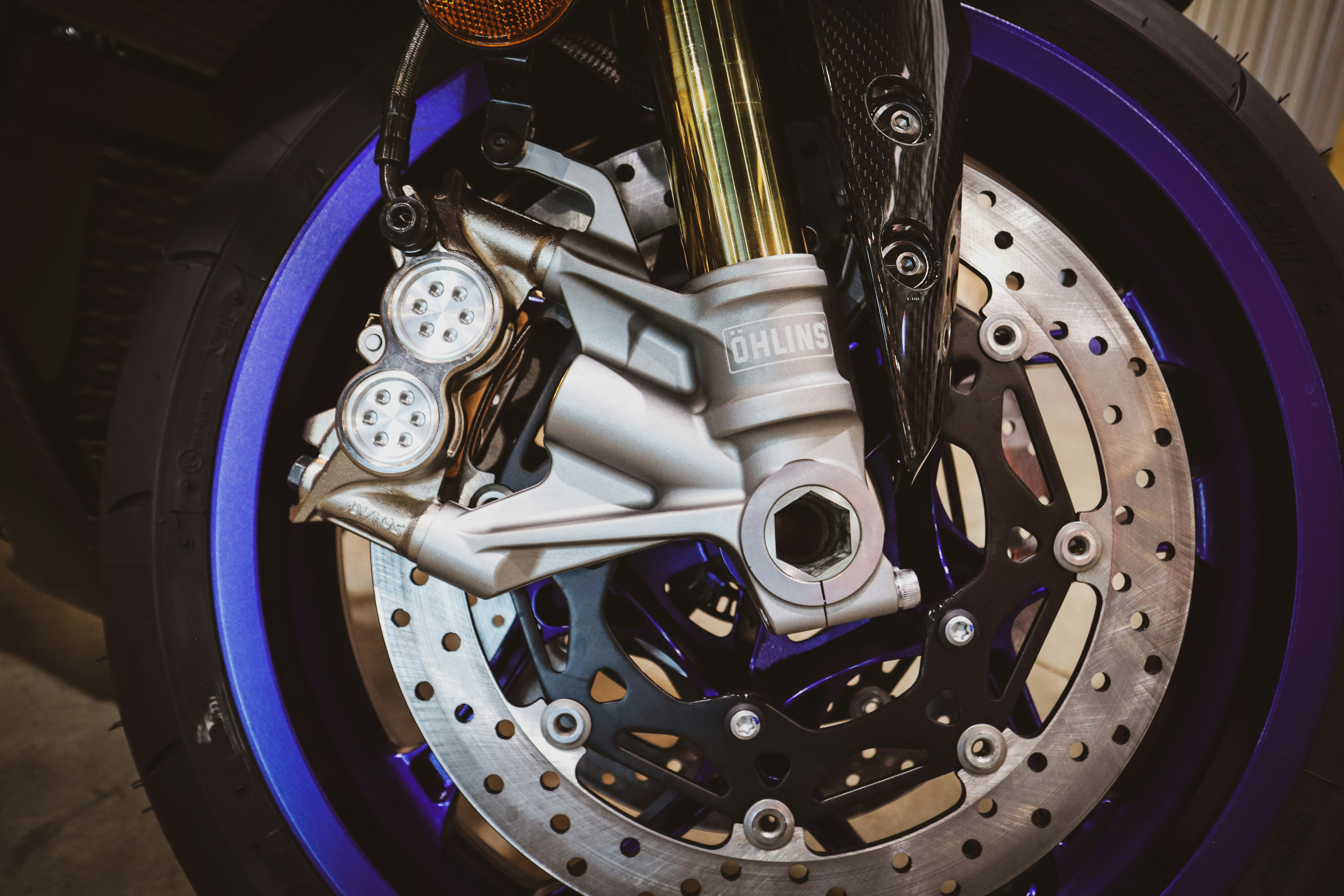 Close-up of a motorcycle's front brake assembly showcasing intricate details of the caliper and rotor design.
