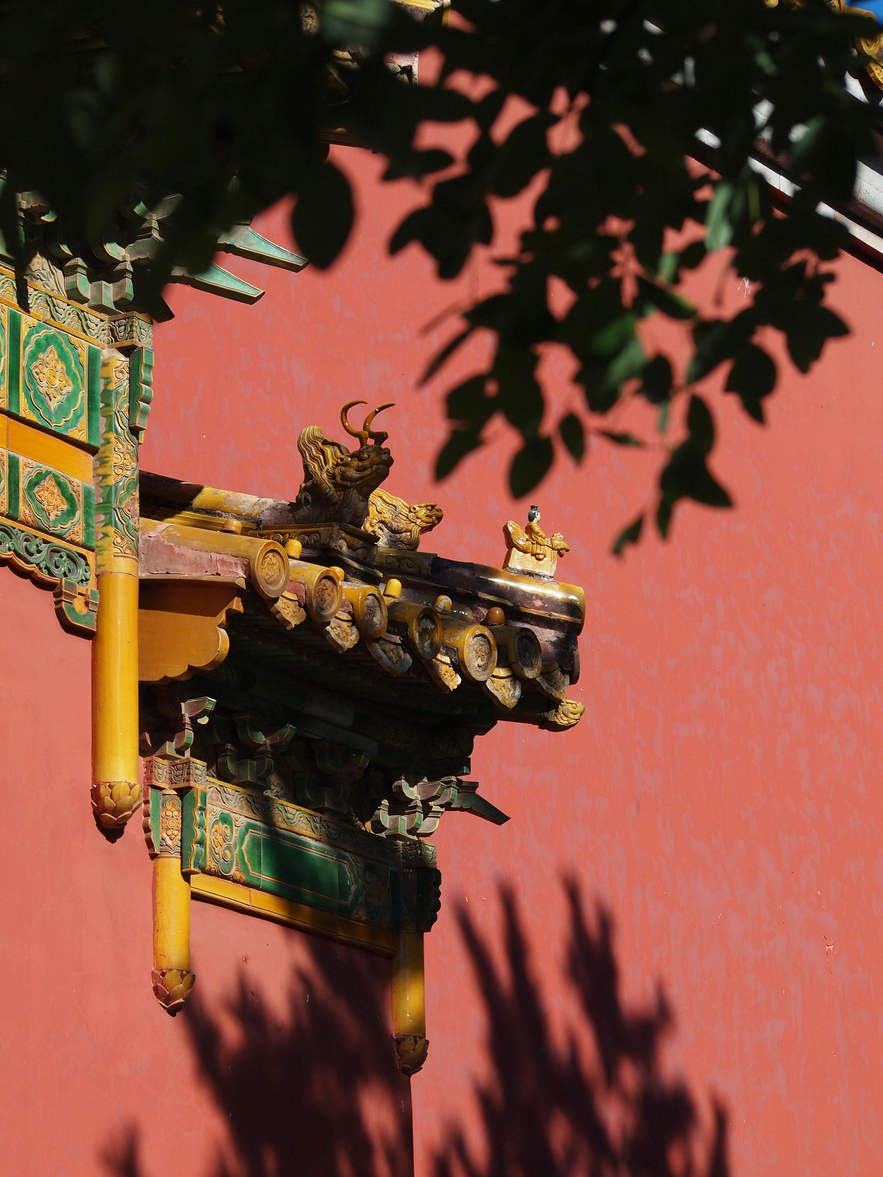 Intricate eaves of traditional architecture adorned with vibrant colors and ornate details against a rich red backdrop.