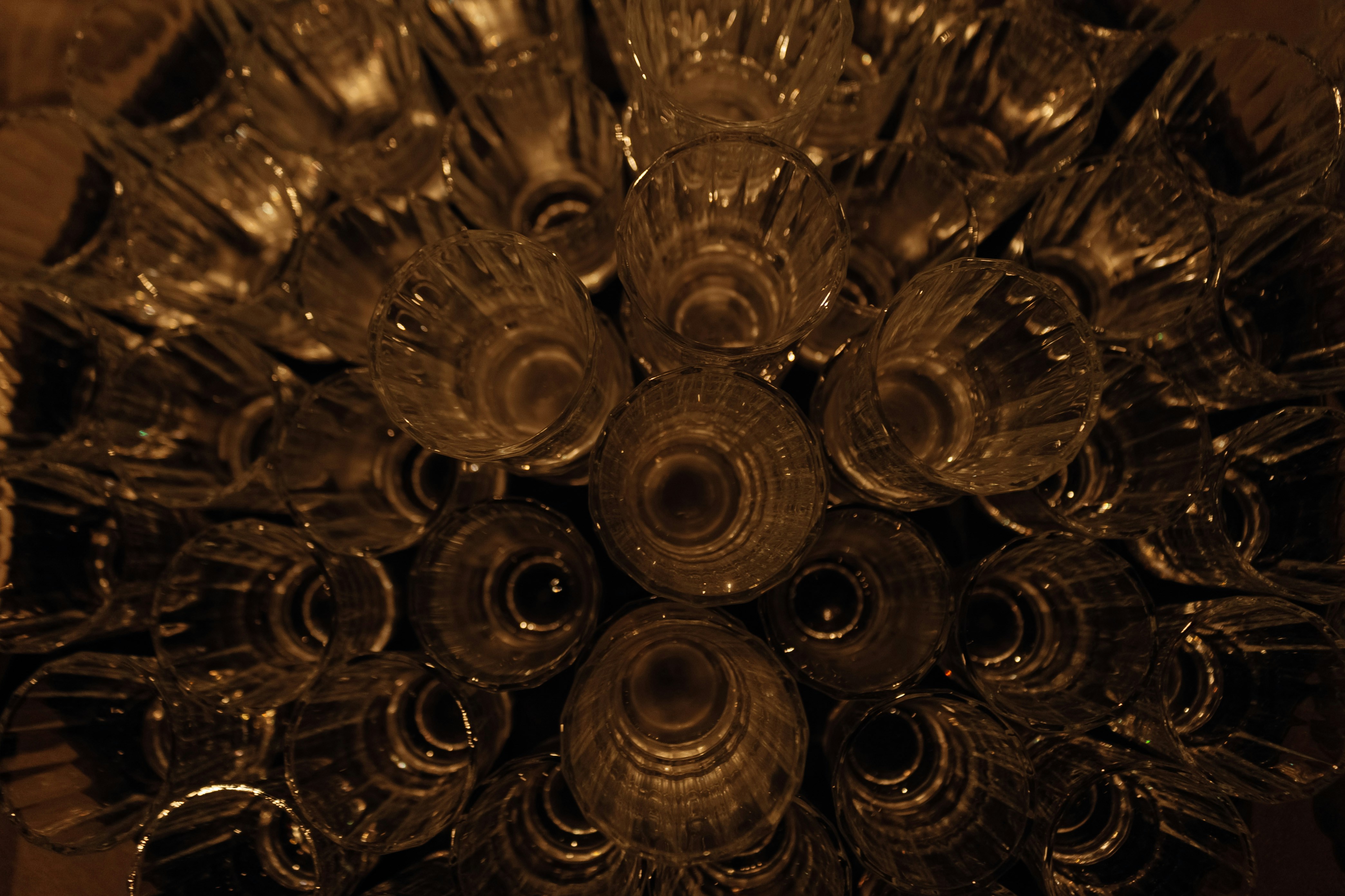An intricate arrangement of crystal glasses viewed from above, showcasing their reflections and patterns against a warm backdrop.