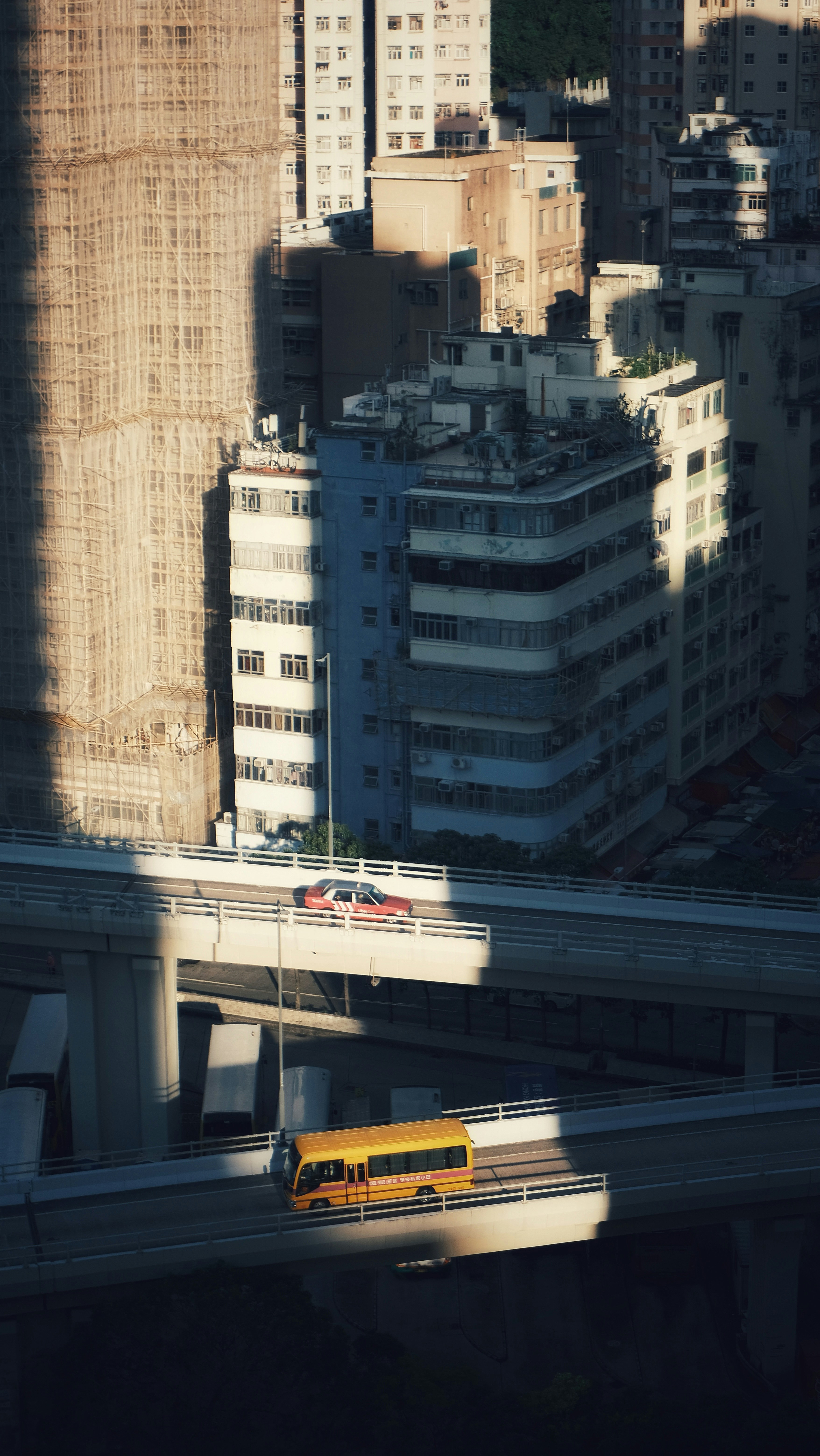 Yellow bus and red car on elevated highway.