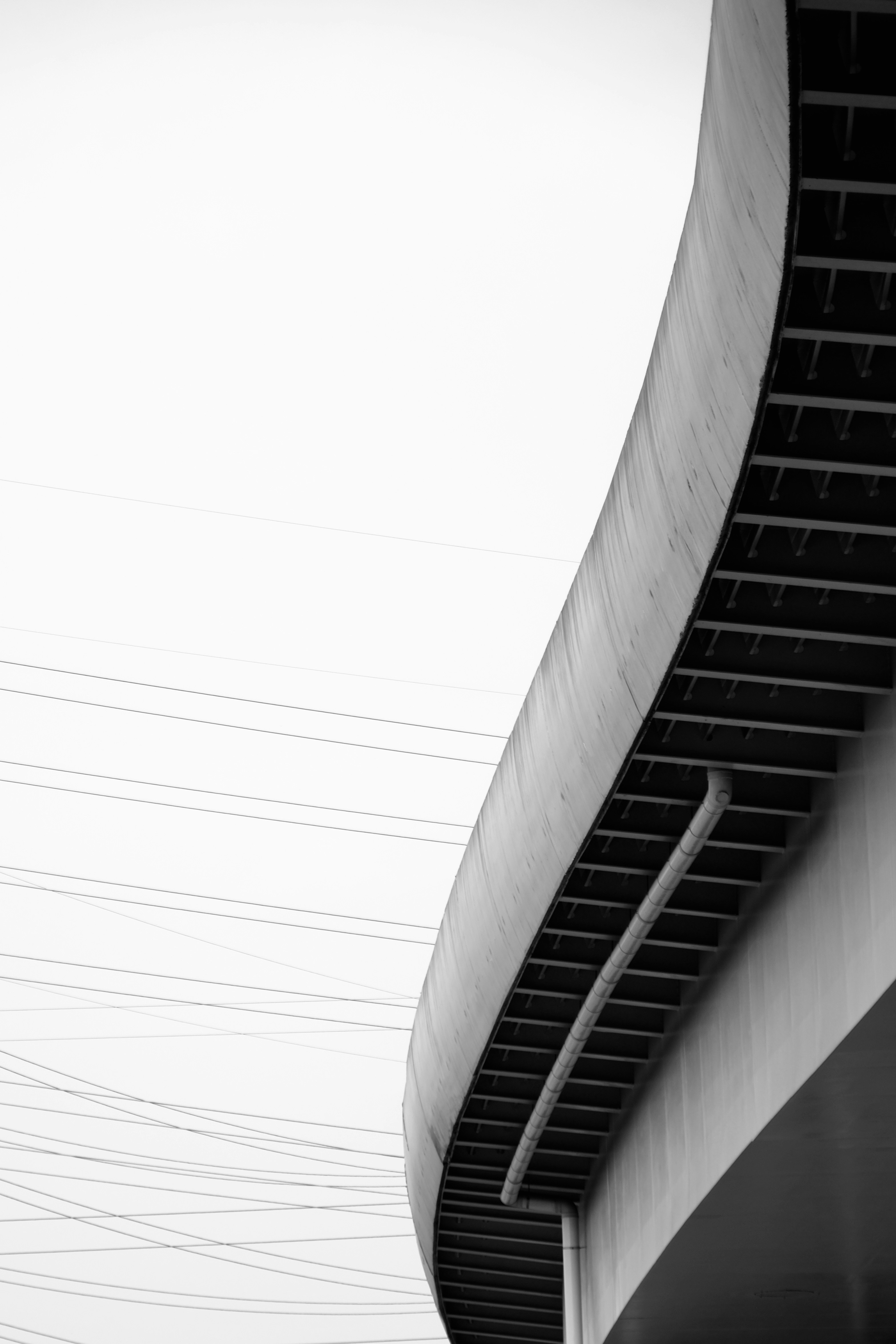 Curving concrete structure with power lines against sky