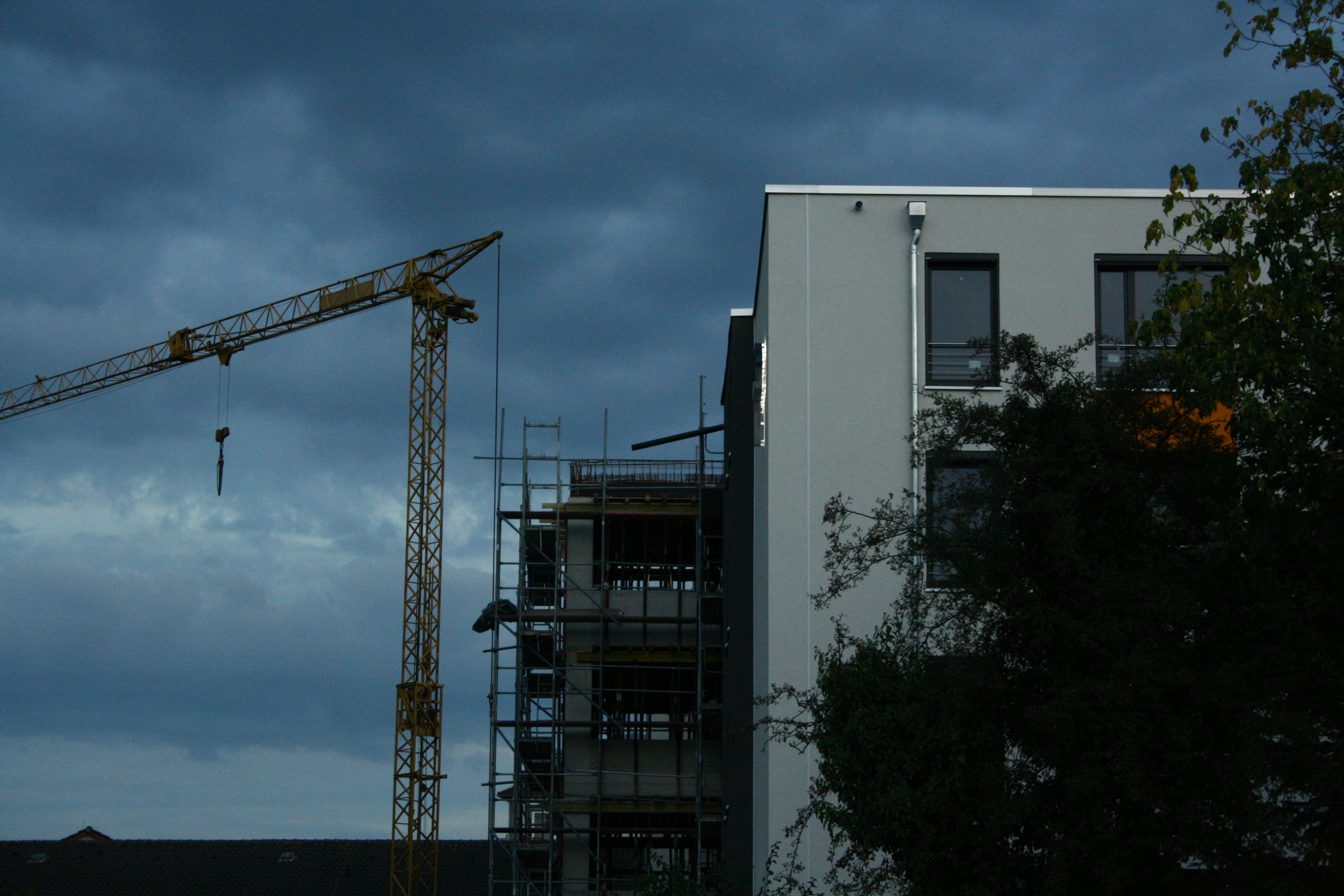 Crane over a skeletal facade under a brooding sky