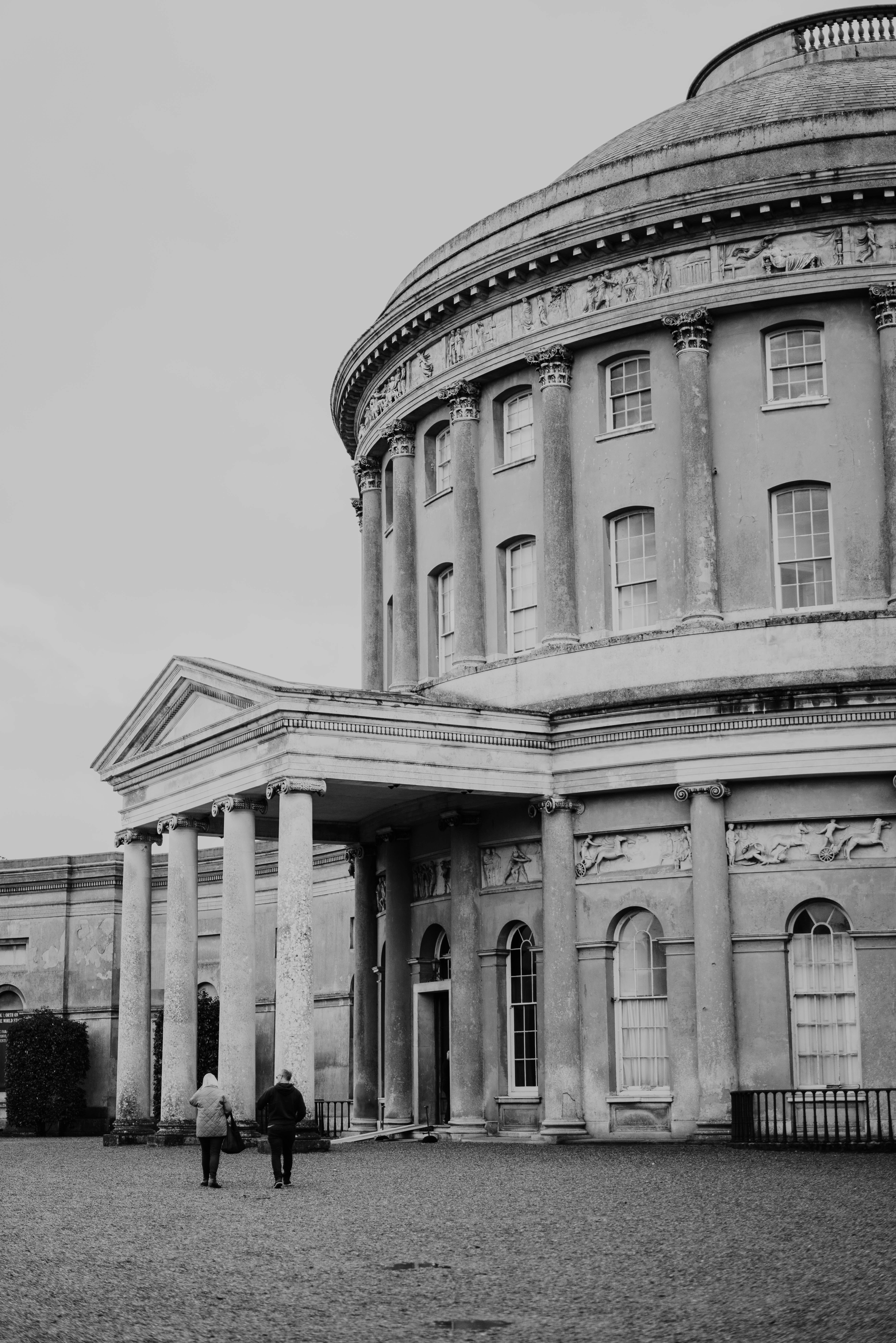 Two people walk towards a grand neoclassical building