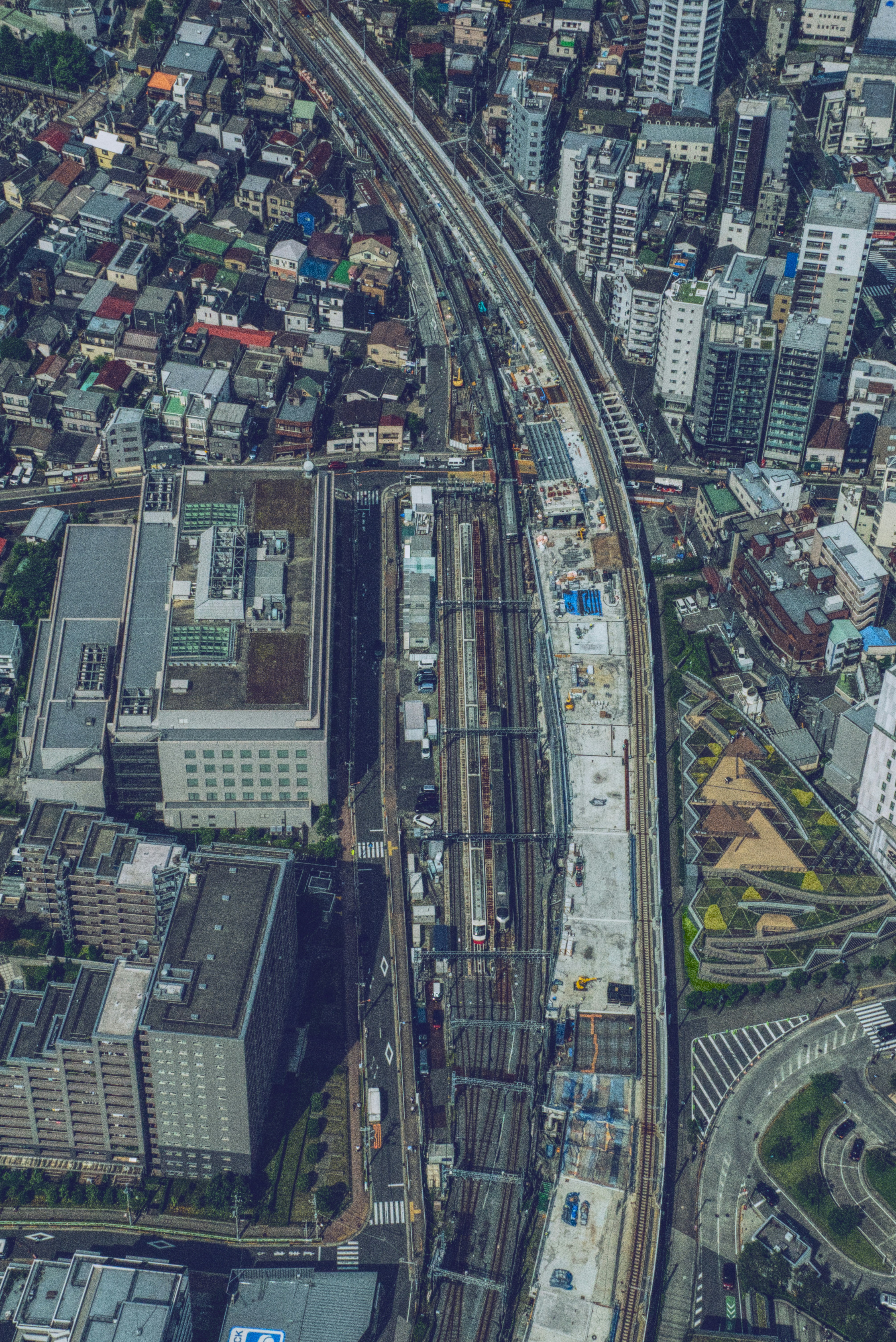 Aerial view of a bustling urban landscape featuring a curved railway track surrounded by buildings and construction sites.