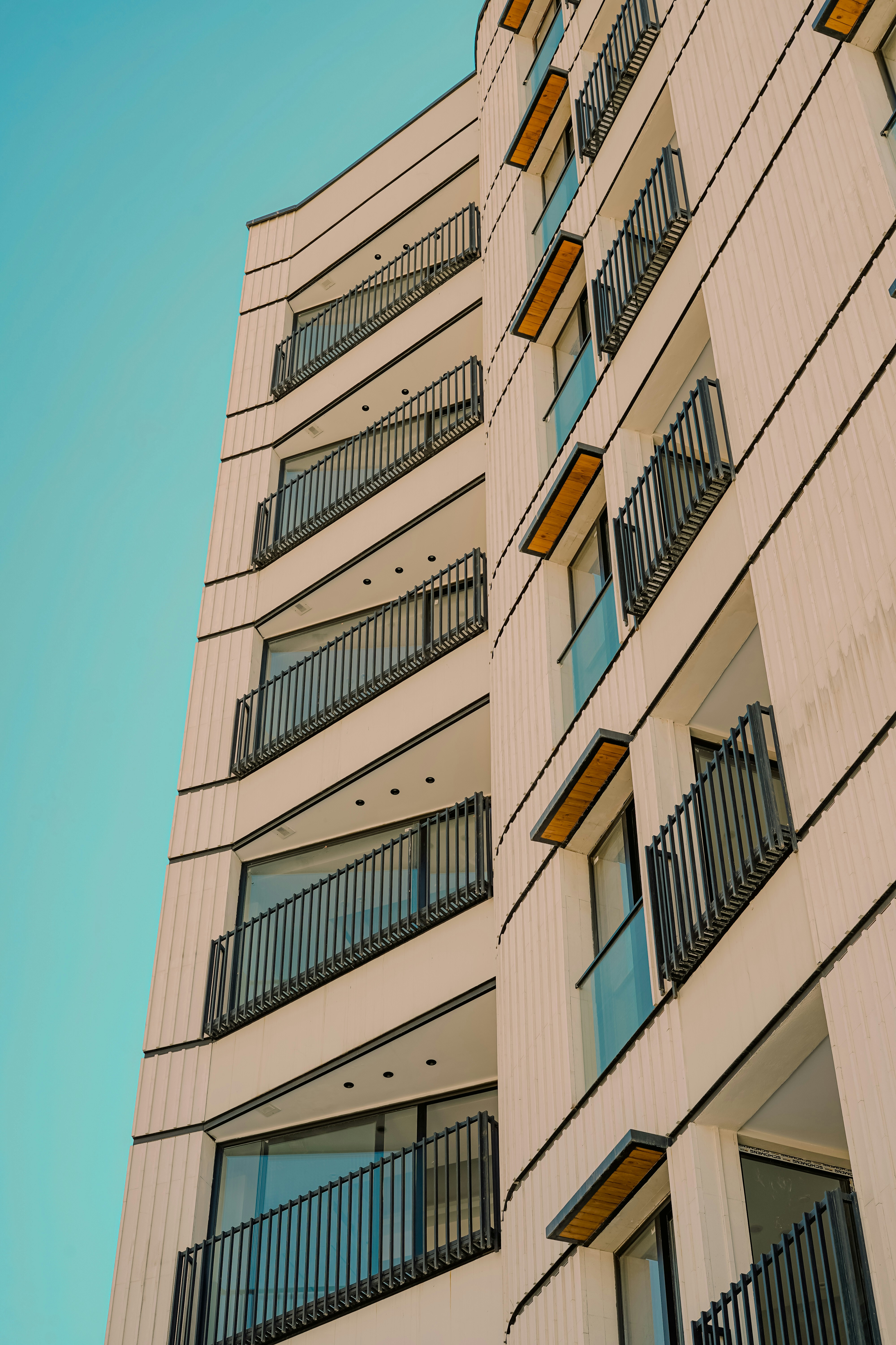 Modern apartment building showcasing sleek lines and balconies against a clear blue sky.