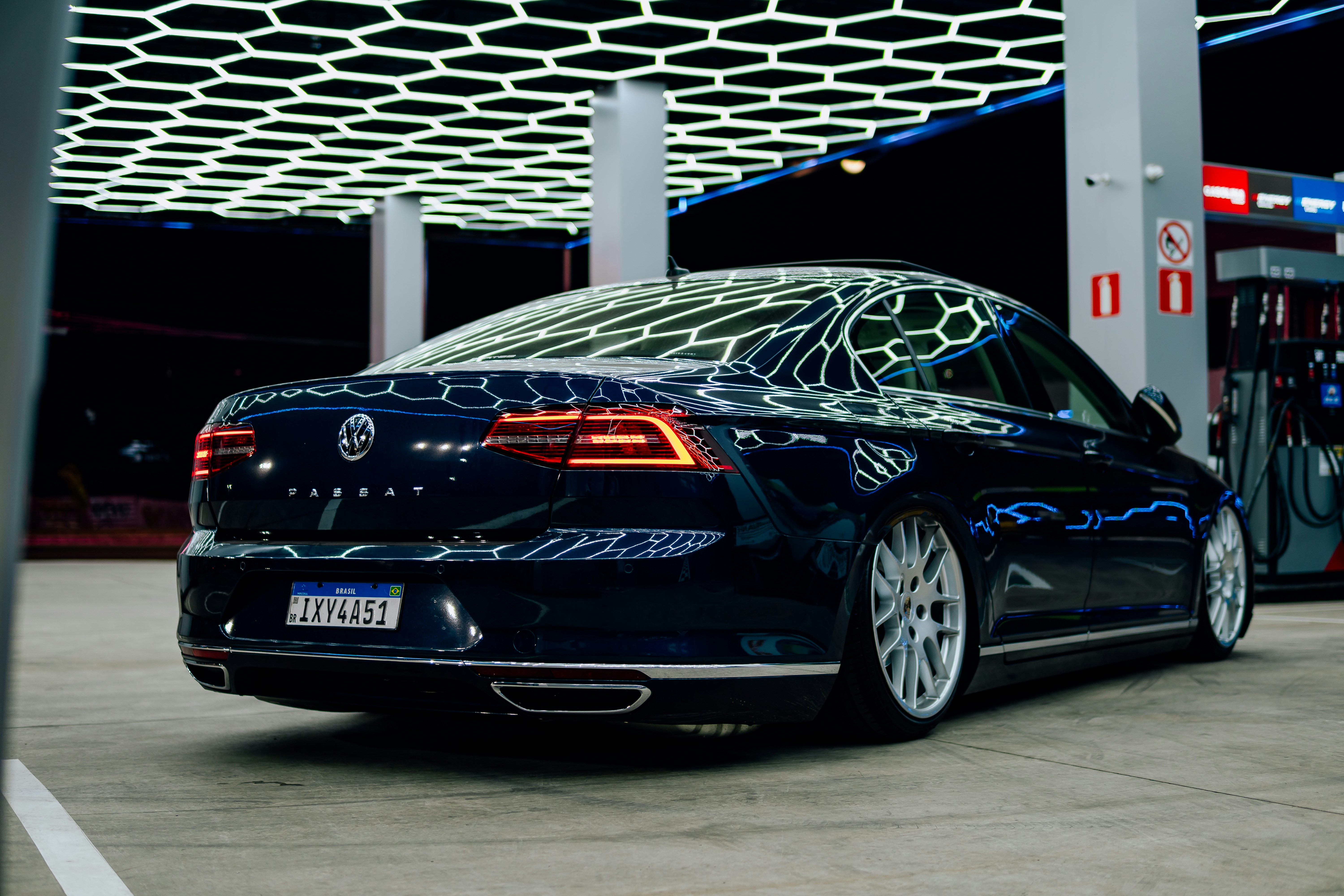 Under the Honeycomb Canopy: A Midnight Blue Passat at a Neon-Faceted Gas Station