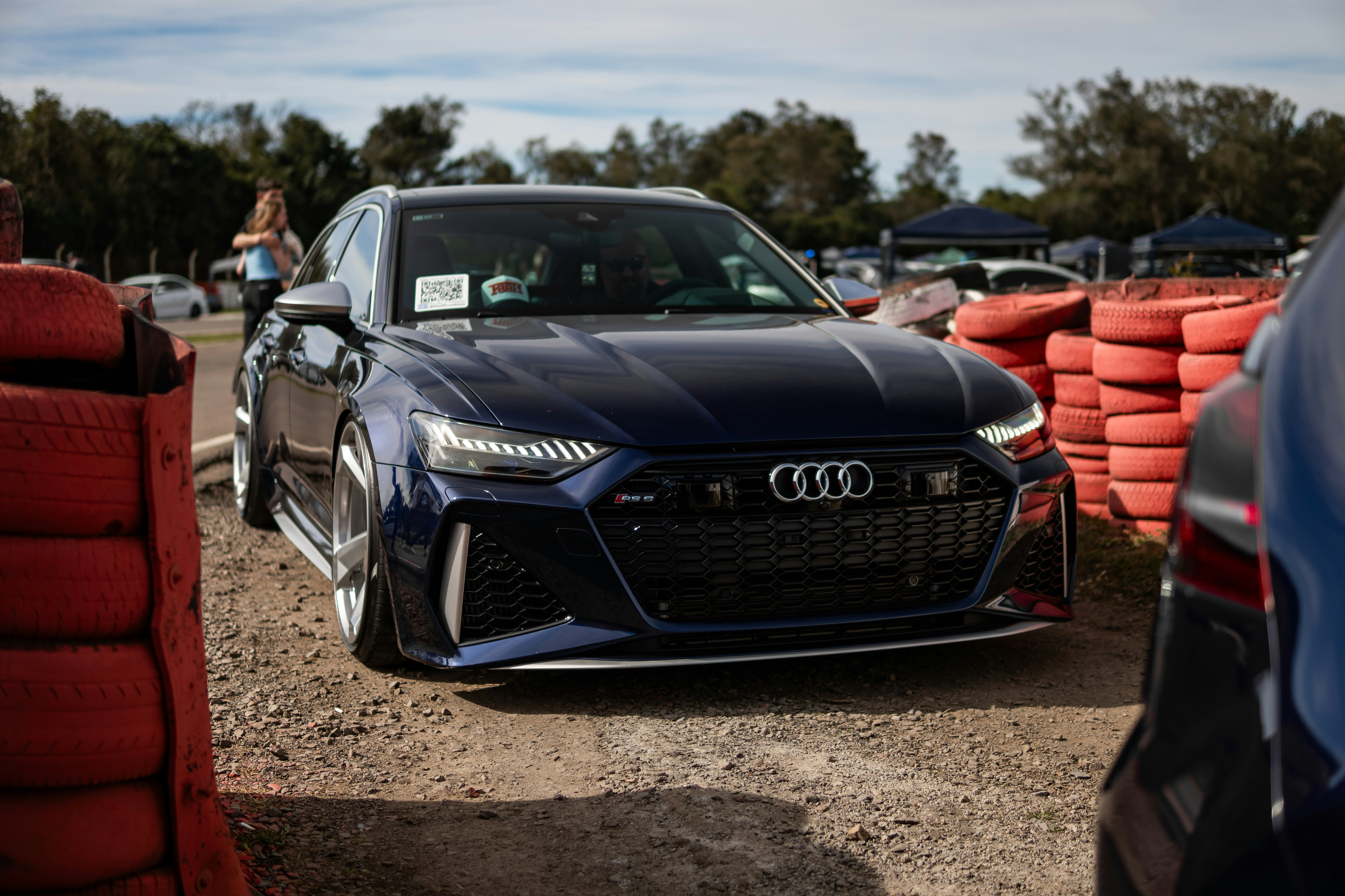 Azure Audi at the Dirt Show: Framed by Red Tire Barricades